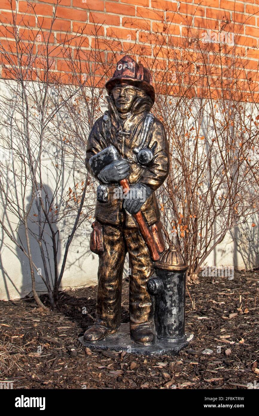A small bronze statue of a firefighter holding an axe beside a fire ...