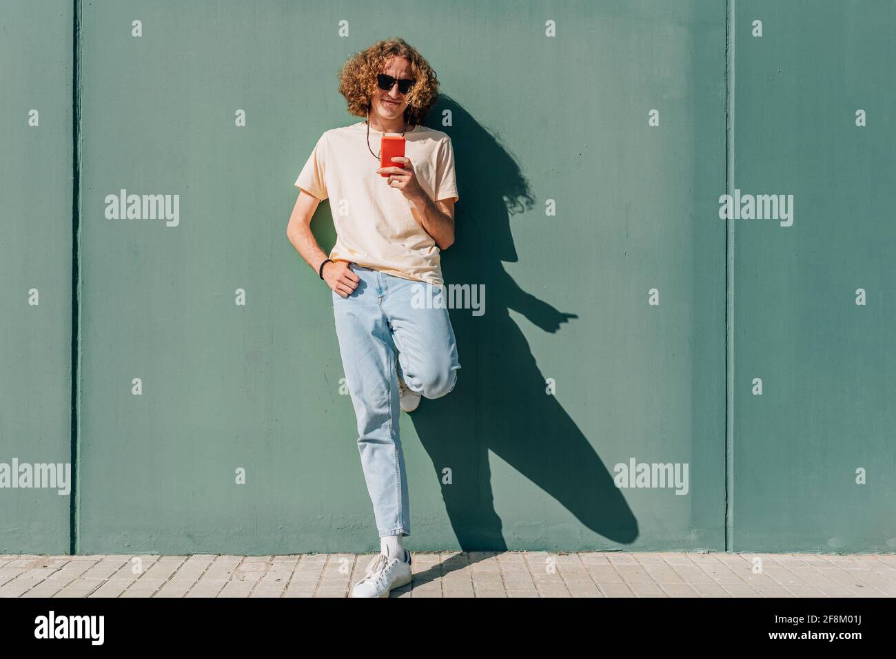 horizontal full body portrait of a young caucasian man using a red ...
