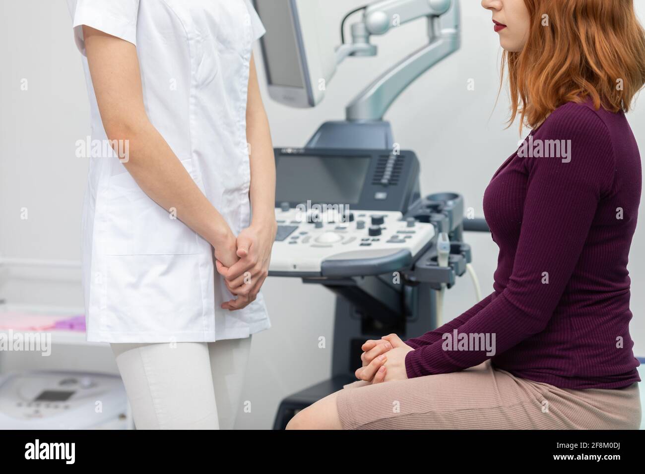 A patient sits in an office equipped with an ultrasound machine and ...