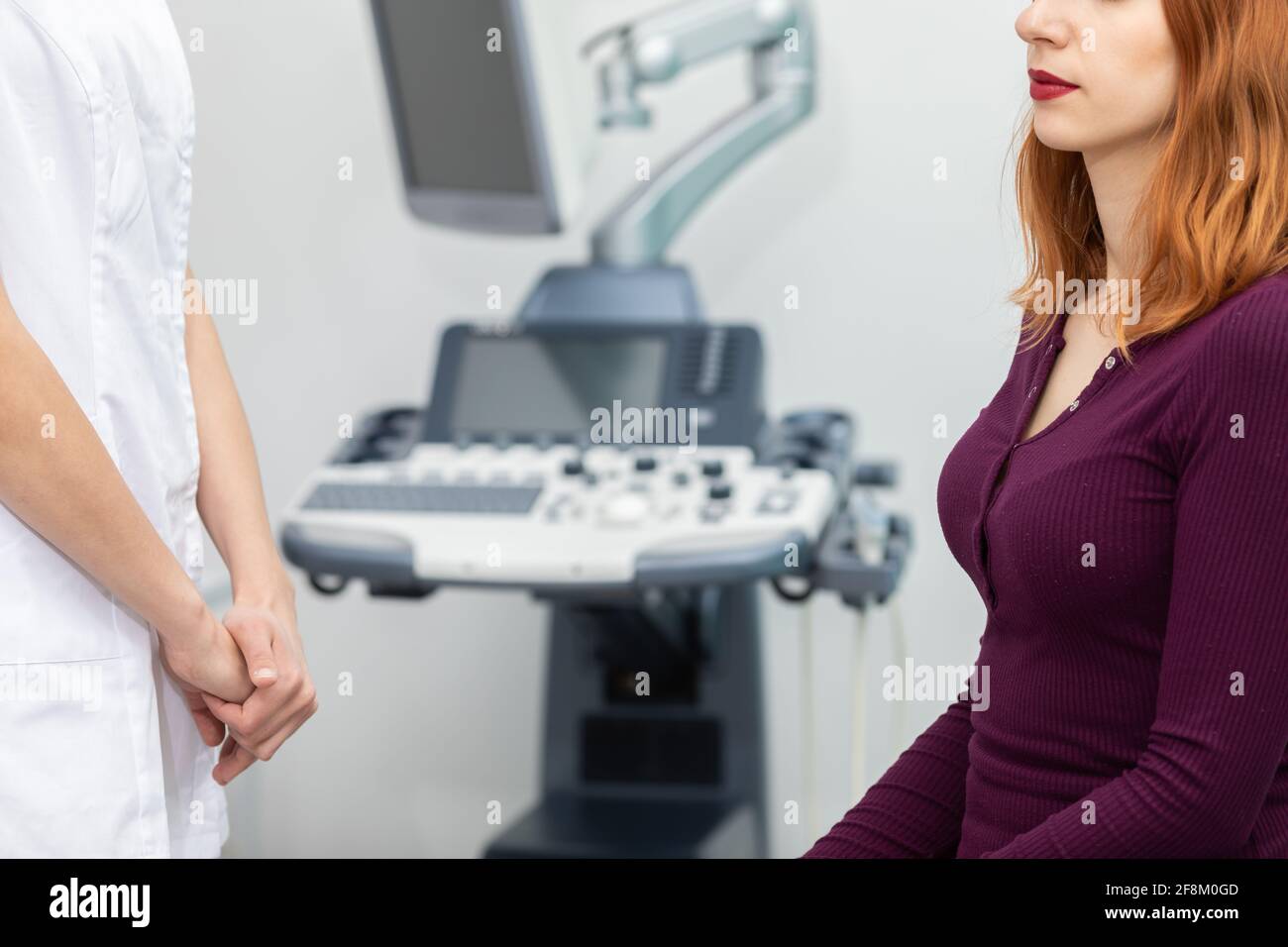 A patient sits in an office equipped with an ultrasound machine and ...