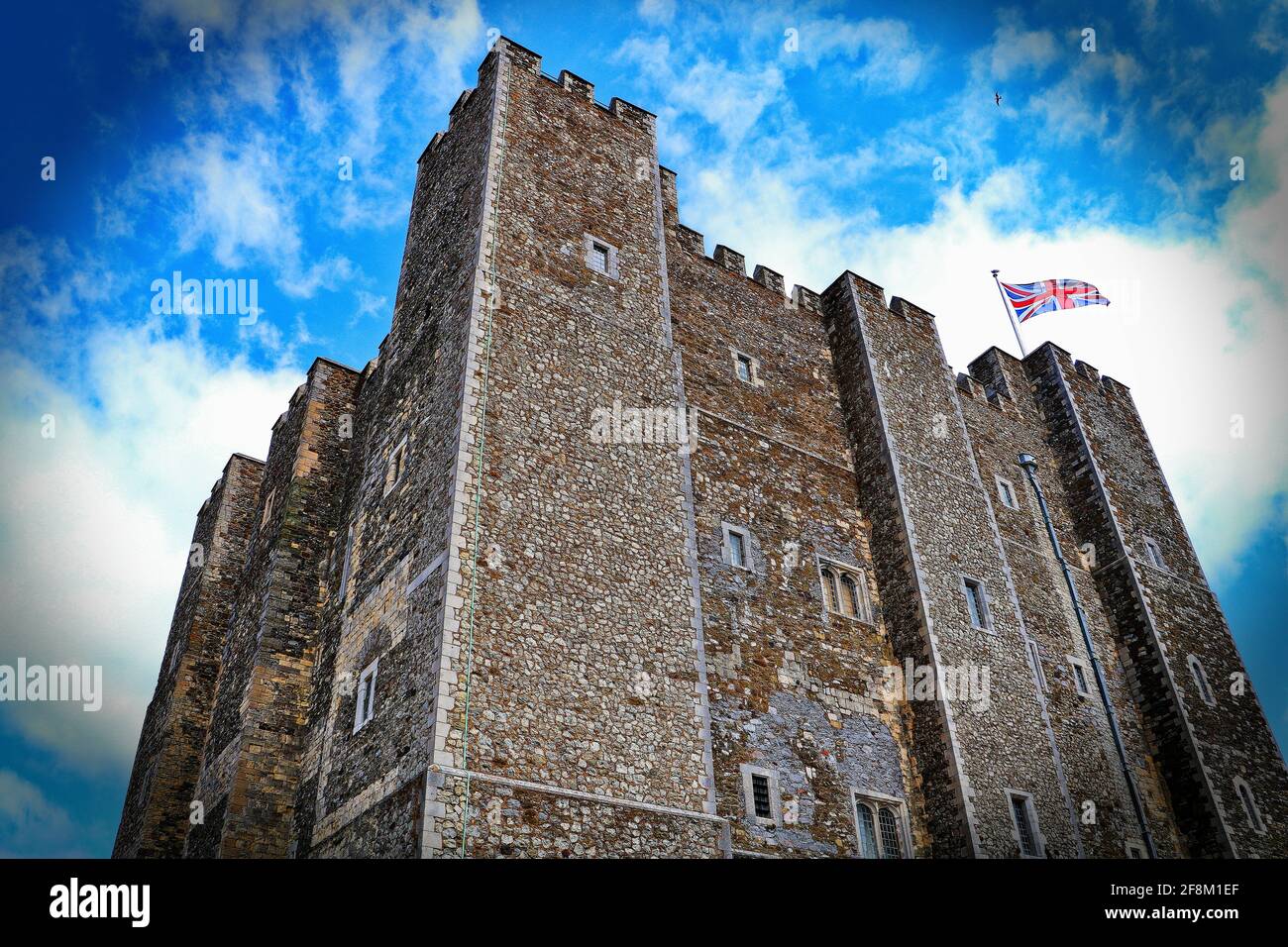 Low angle shot of a tall brick building with the UK flag waving on top ...