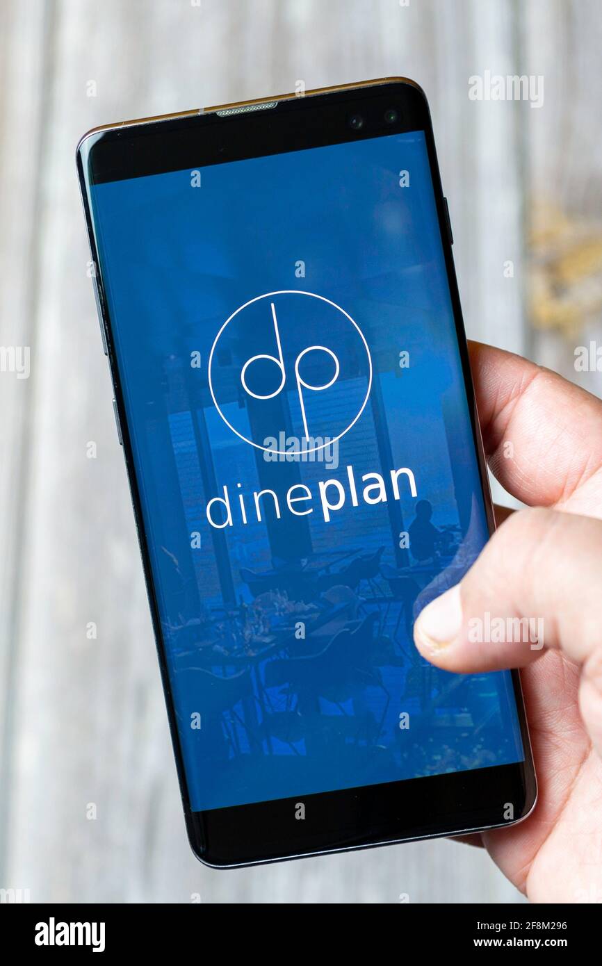 A Mobile phone or Cell phone being held in a hand showing the Dineplan app on screen Stock Photo ...