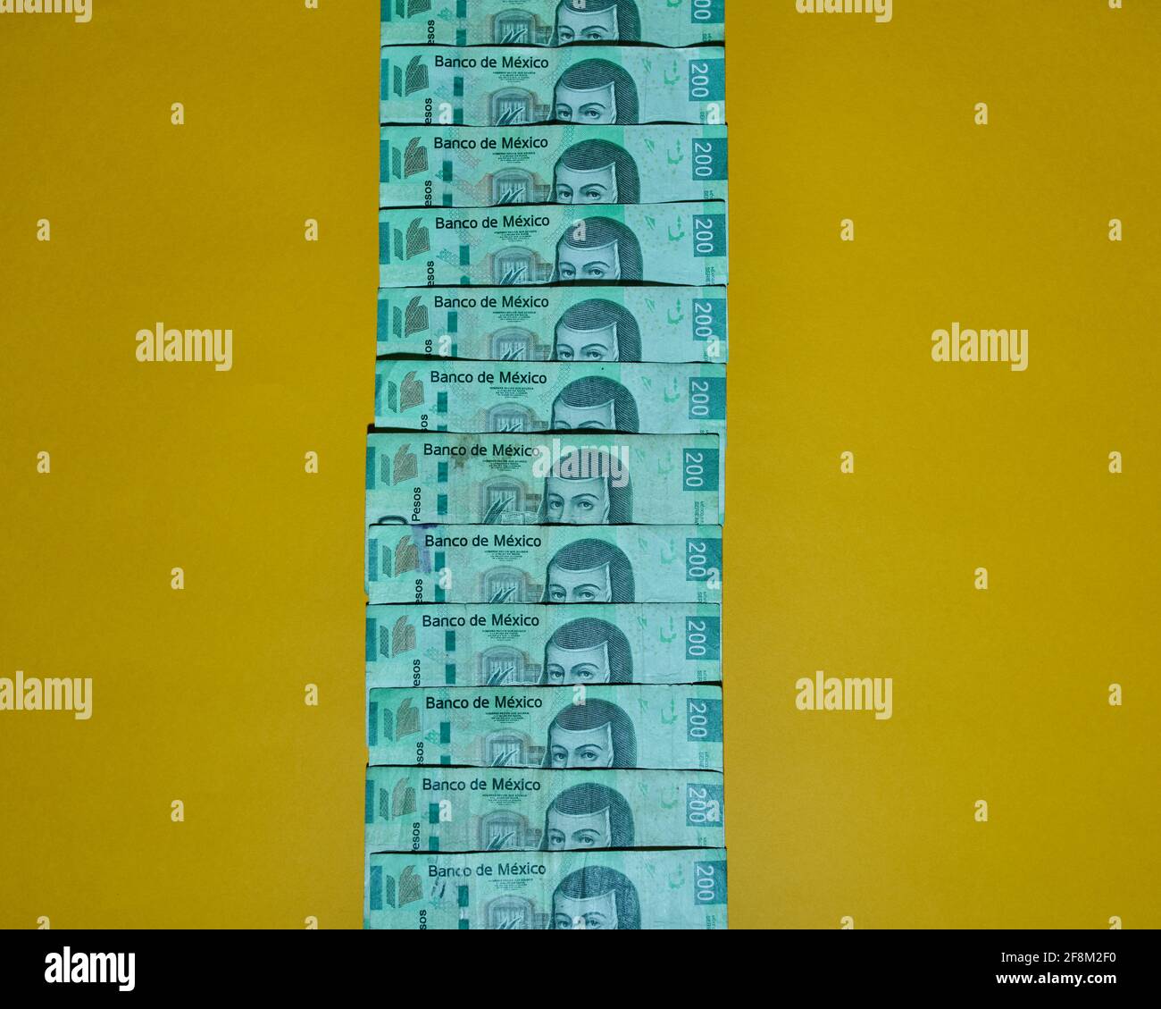 Top view of Mexican banknotes arranged in a row isolated on yellow ...
