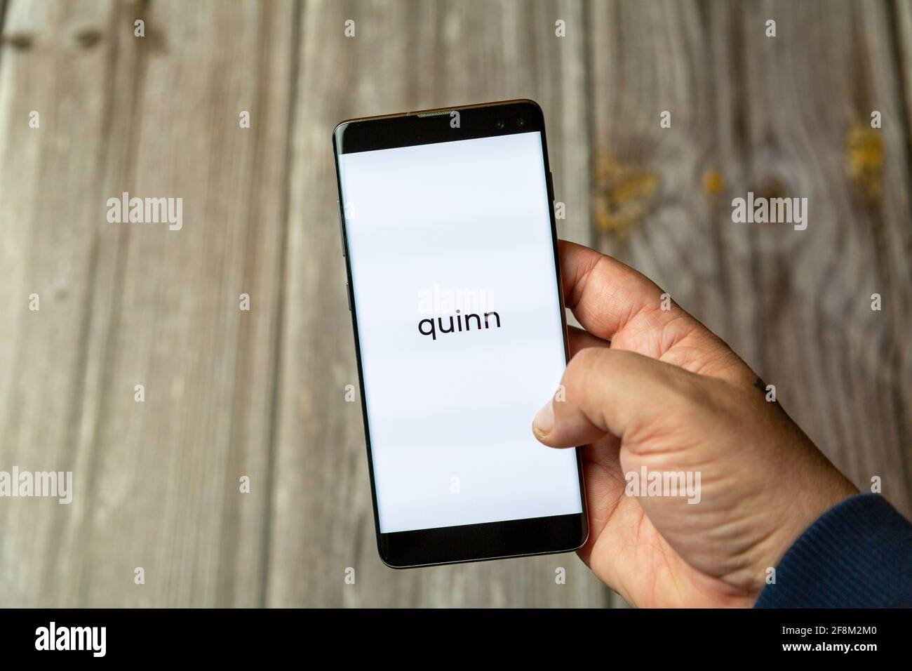 A Mobile phone or Cell phone being held in a hand showing the Quinn app ...