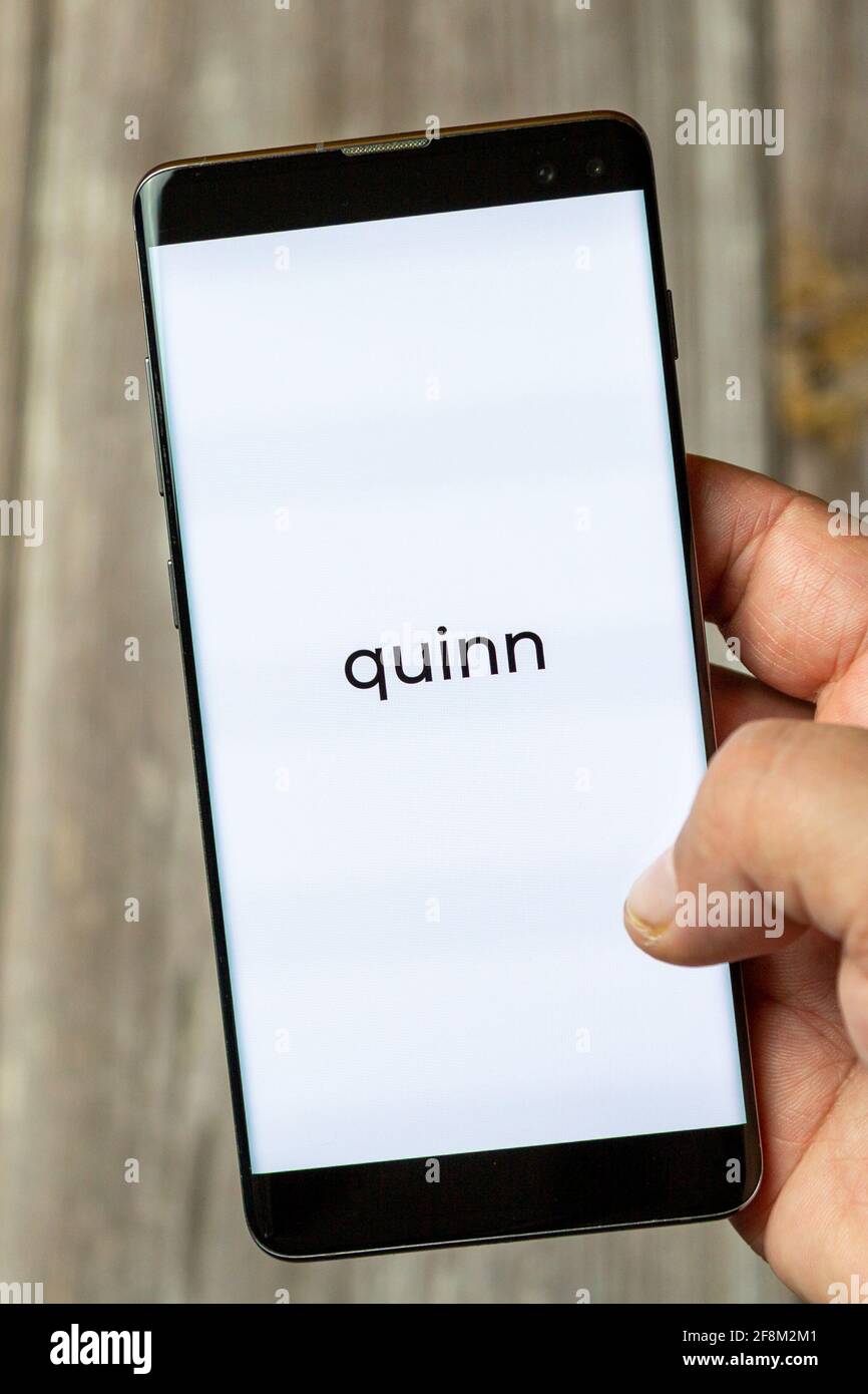A Mobile phone or Cell phone being held in a hand showing the Quinn app ...
