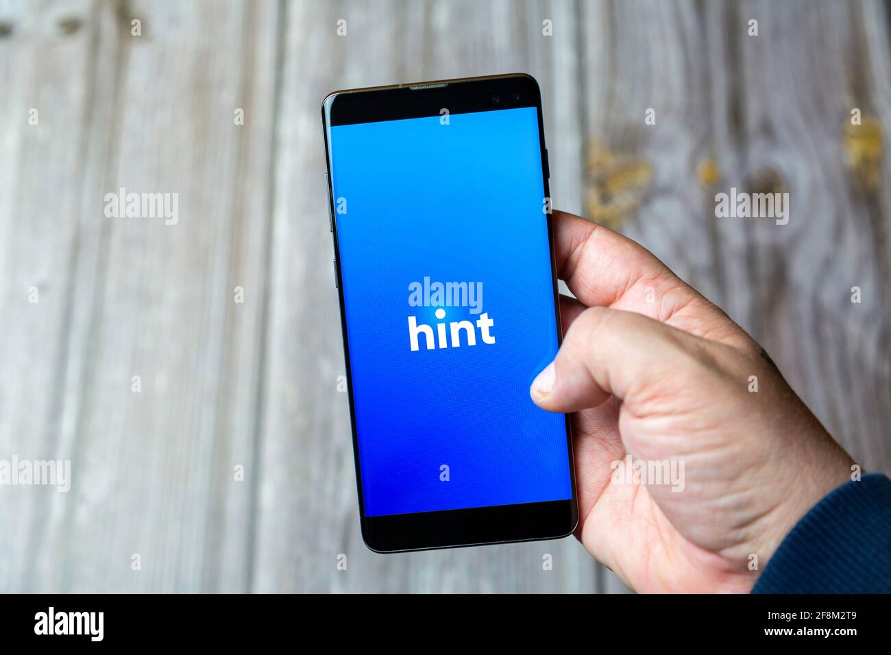 A Mobile phone or Cell phone being held in a hand showing the Hint app ...