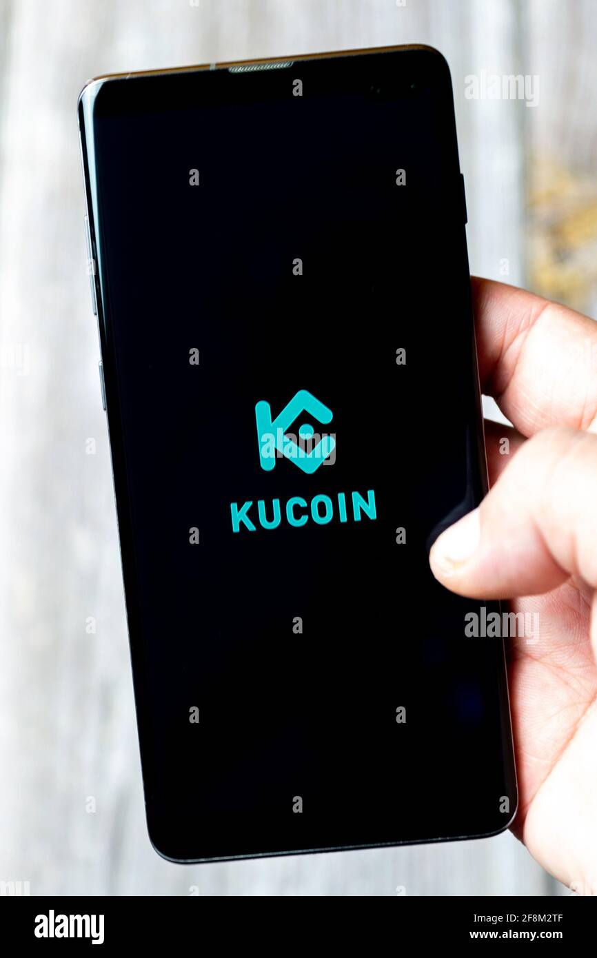 A Mobile phone or Cell phone being held in a hand showing the Kucoin ...
