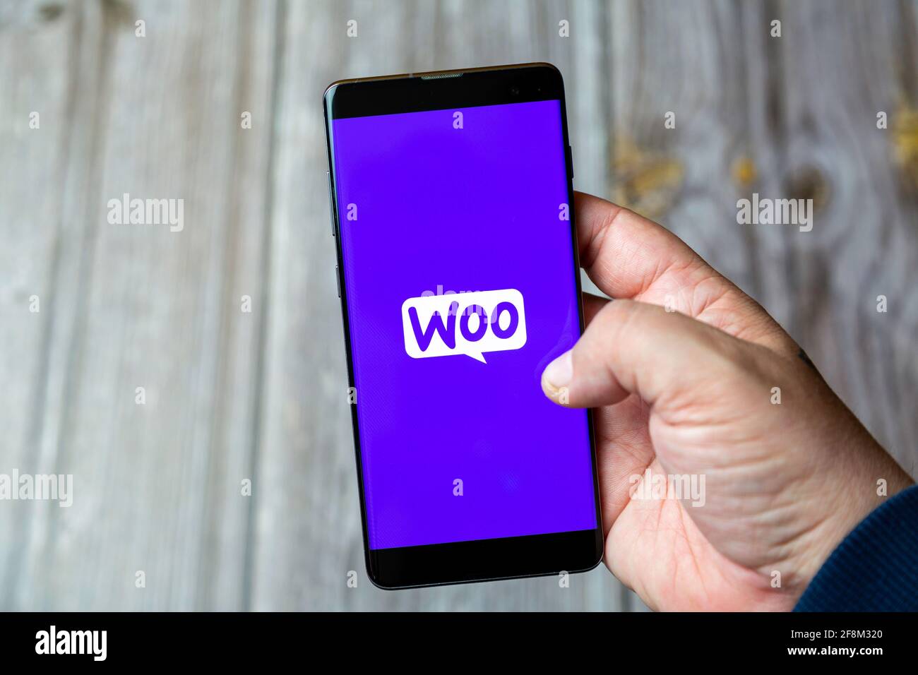 A Mobile phone or Cell phone being held in a hand showing the Woo app ...