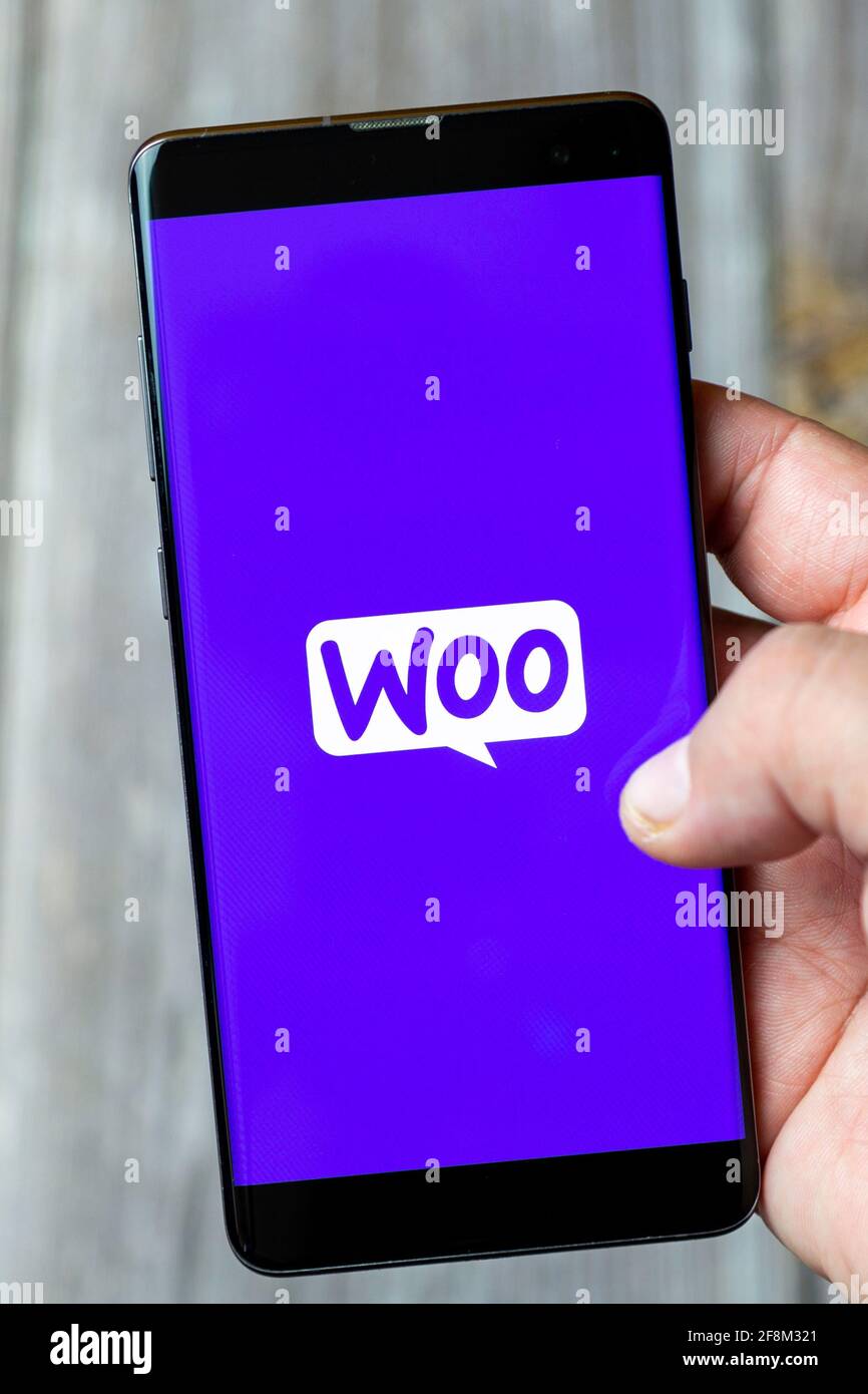 A Mobile phone or Cell phone being held in a hand showing the Woo app ...