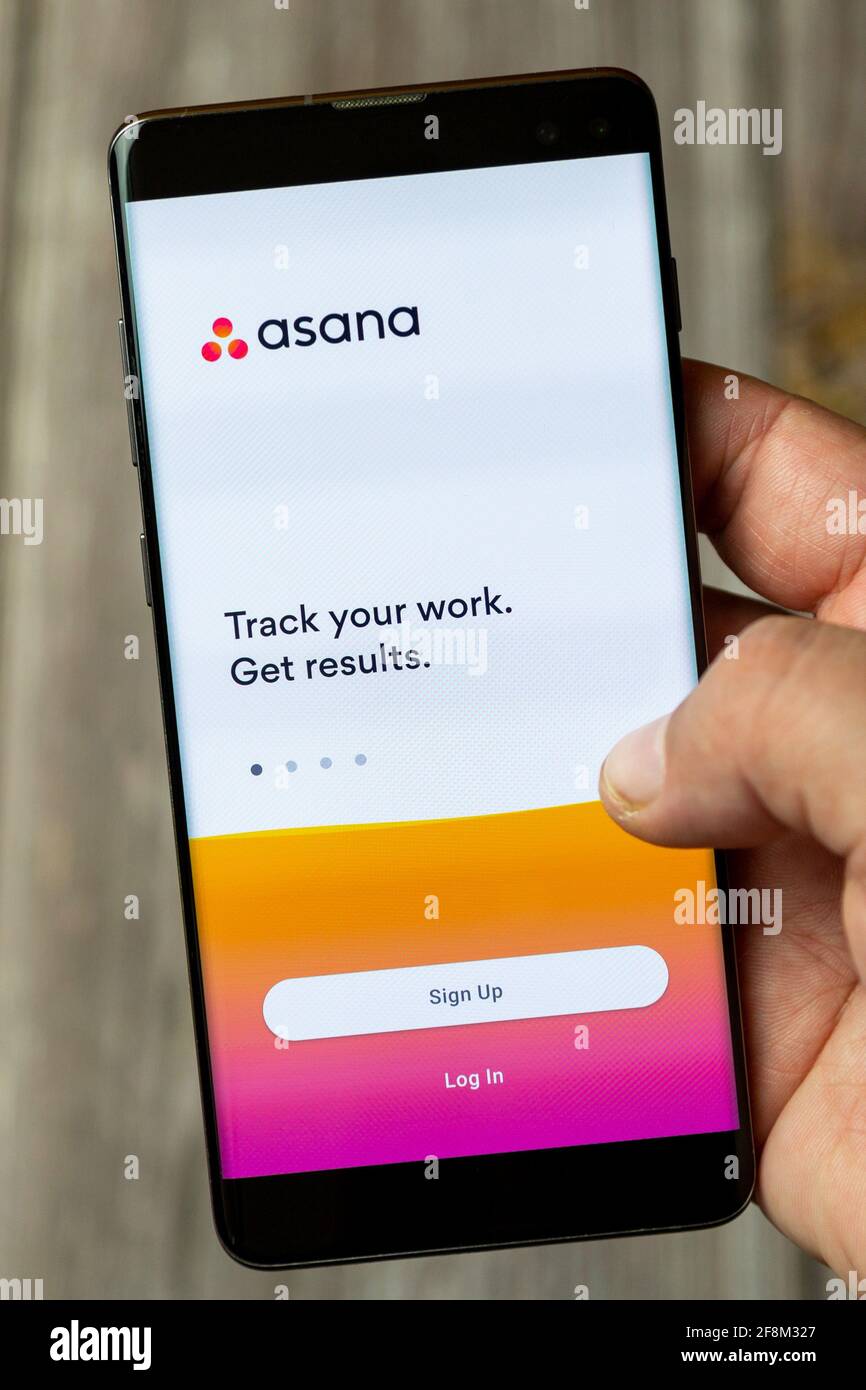 A Mobile phone or Cell phone being held in a hand showing the asana app ...
