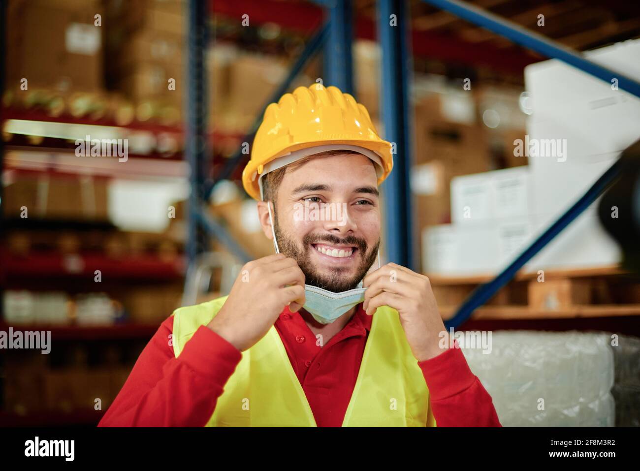 happy worker in a warehouse wearing a safety mask for the prevention of ...