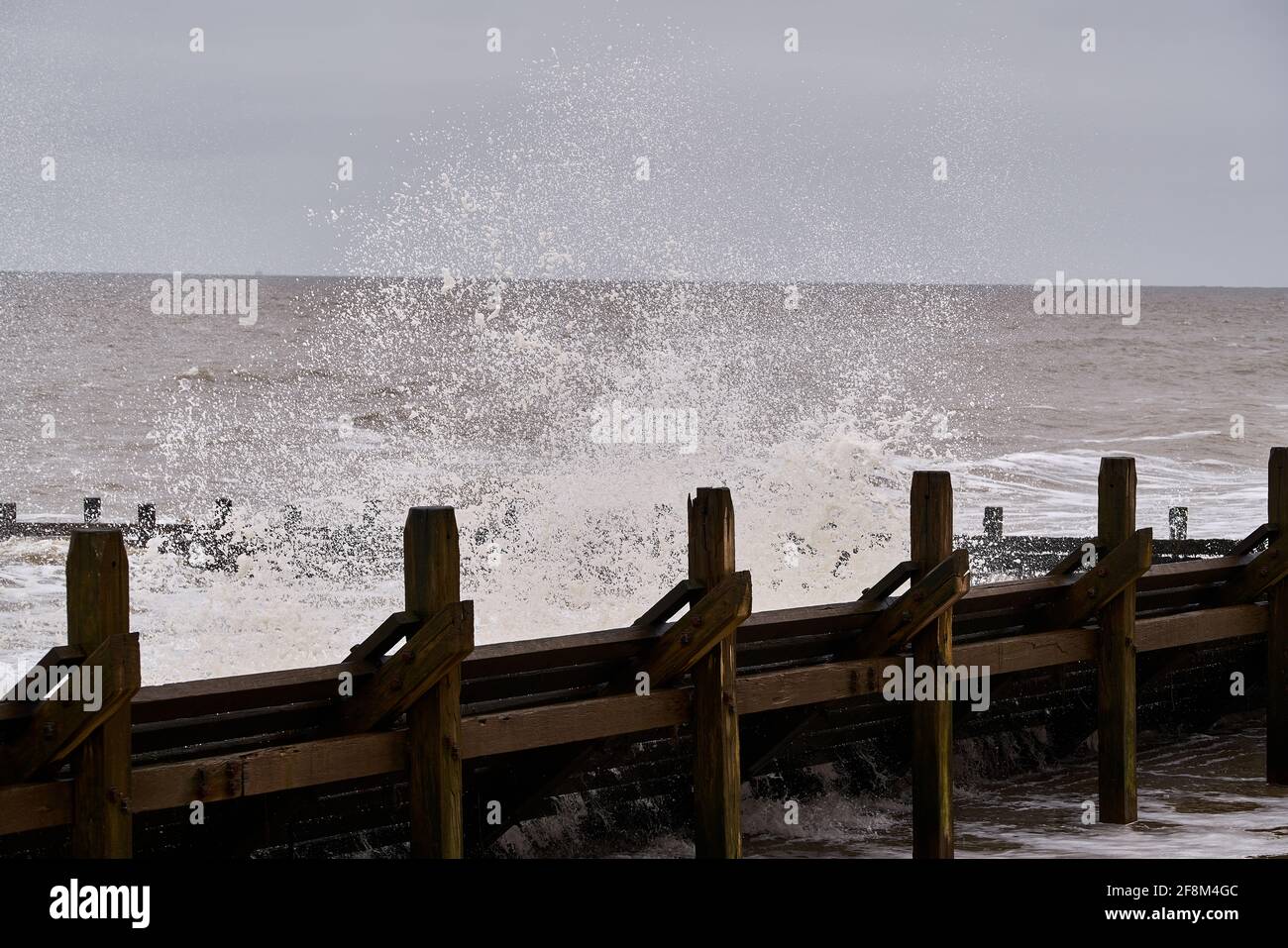 Beautiful shot of the waves breaking on the coast fenced with a wooden ...