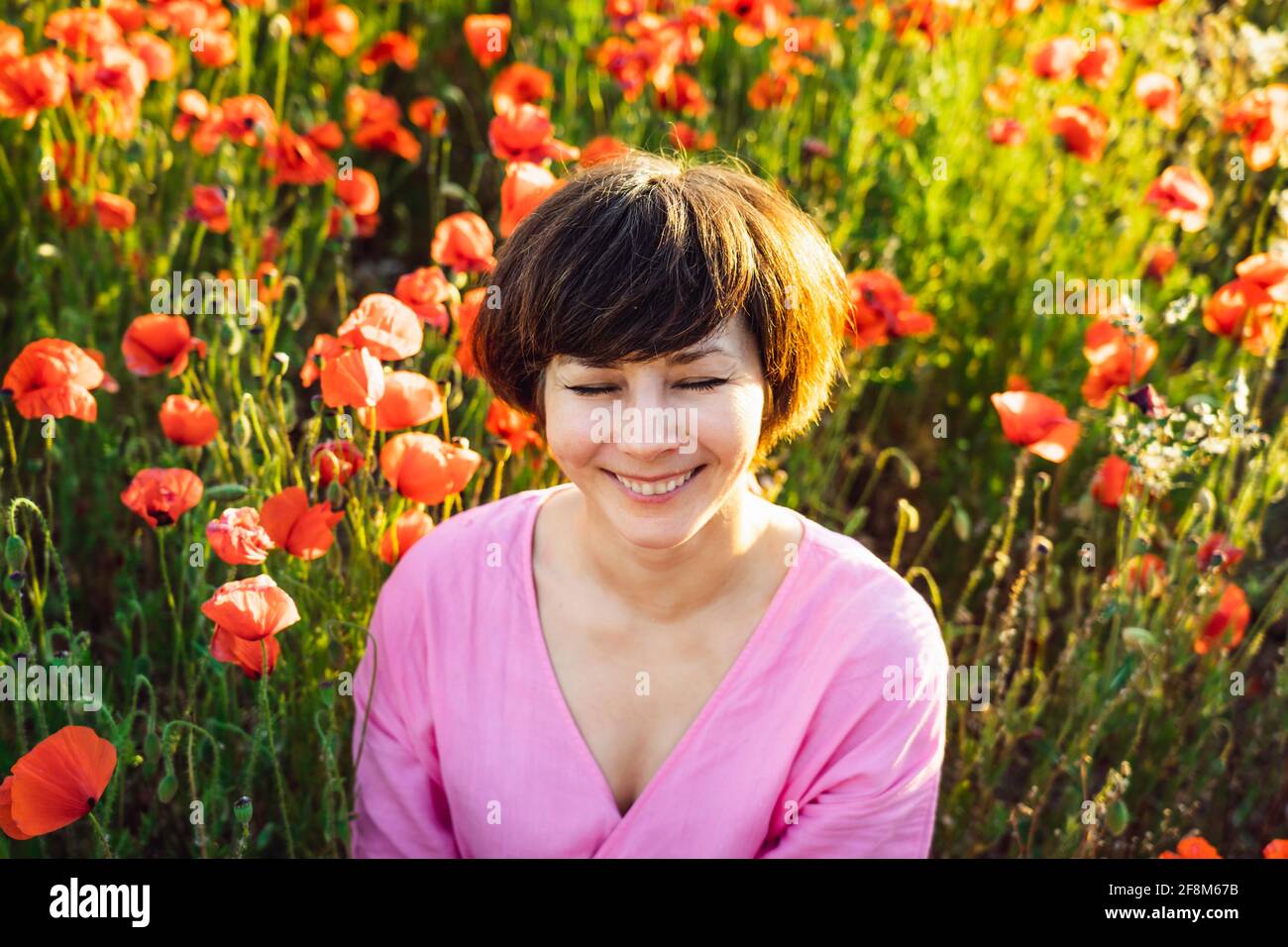 Close up portrait of happy laughing woman with closed eyes in a pink ...