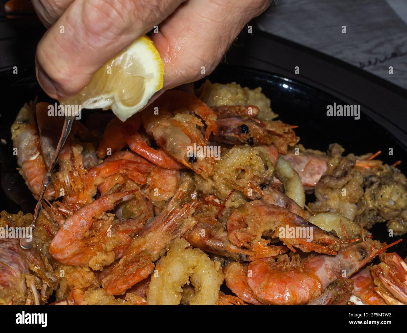 frying fish with hand squeezing a slice of lemon Stock Photo - Alamy