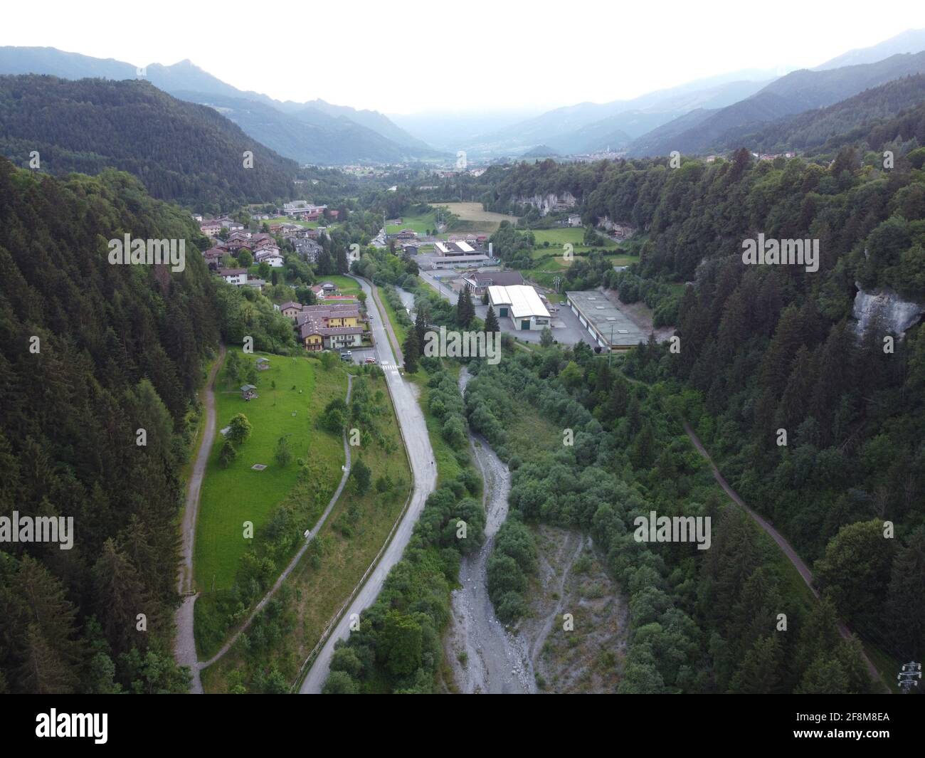 Aerial view of a village surrounded by mountains covered by foliage ...