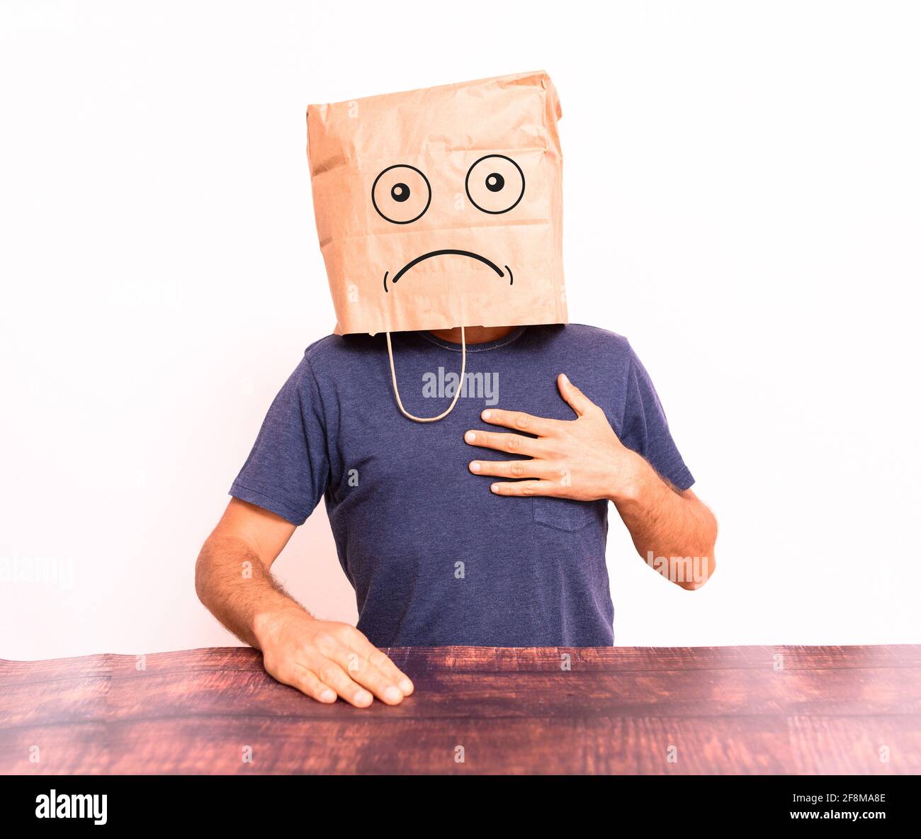 Mature man crestfallen, hiding his identity behind a paper bag over his ...