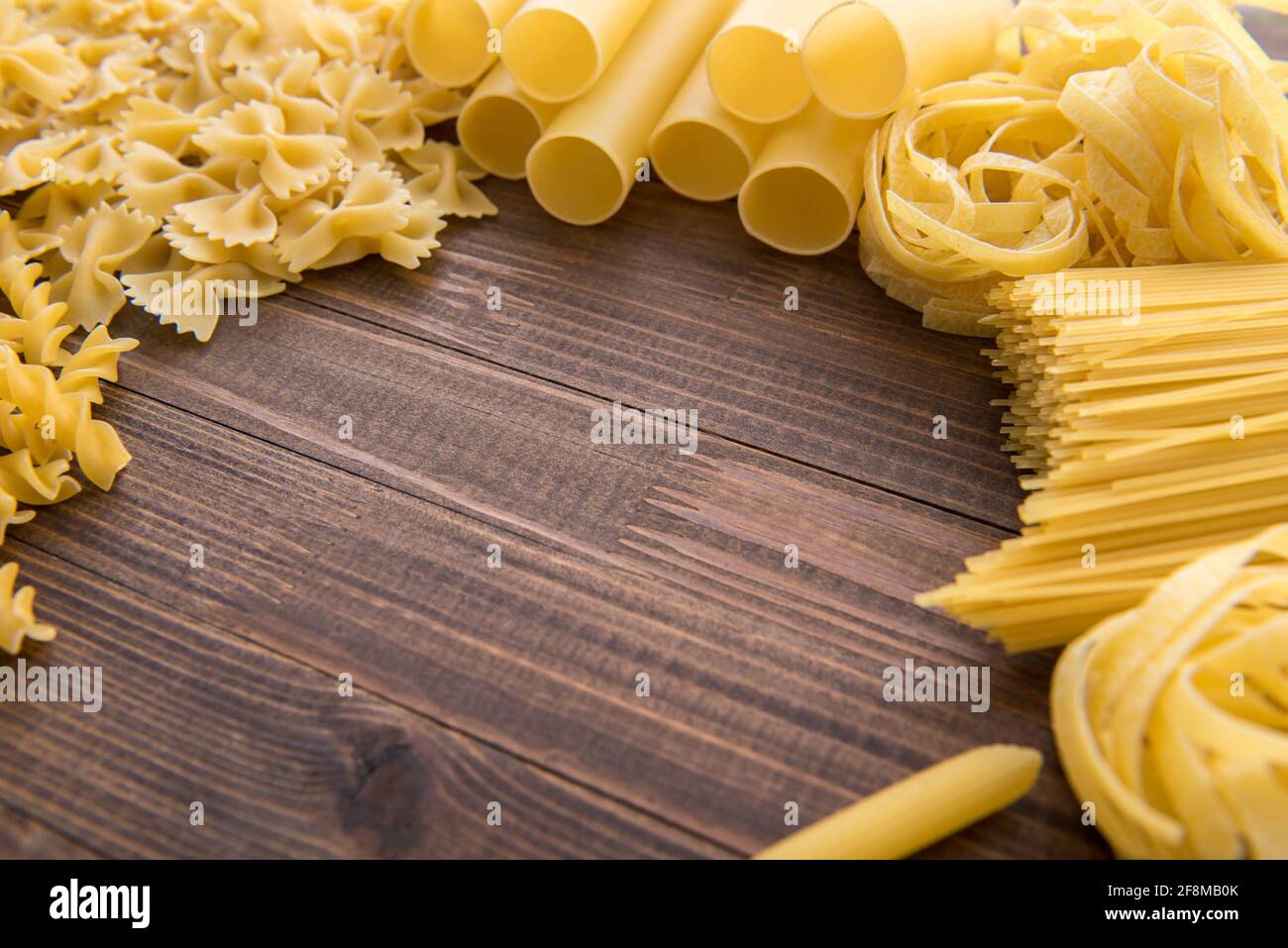 Different kinds of pasta on a wooden background. Farfalle, fettuccine ...
