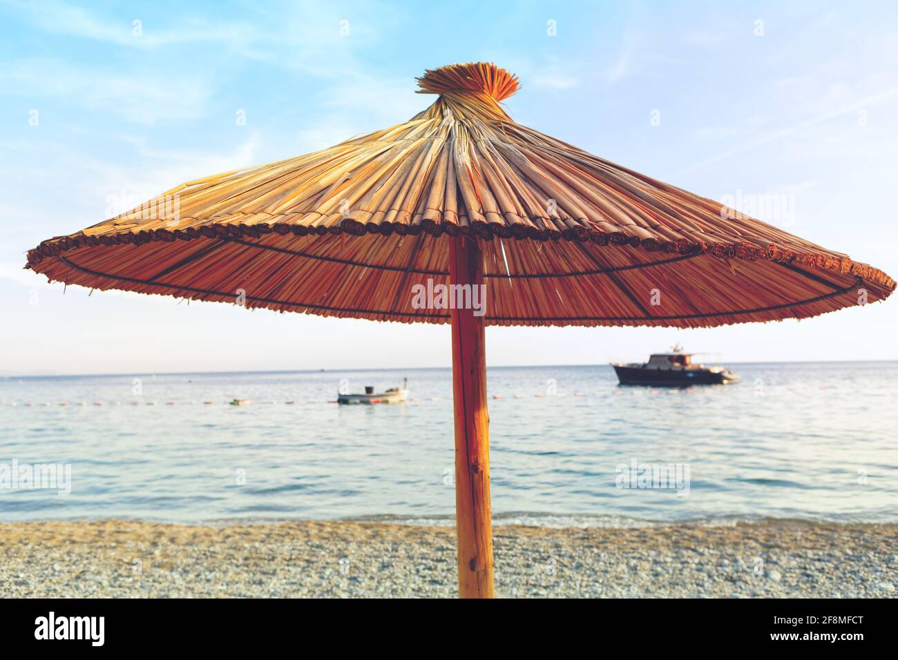 Beach umbrella at exotic coast with boats at background . Tropical ...