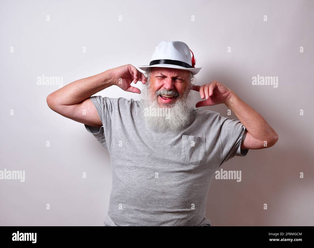 Retired American male with a long white beard plugging ears with this ...