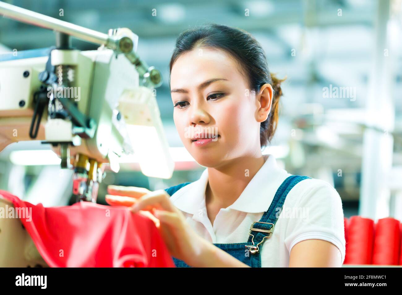 Seamstress or worker in a chinese factory sewing with a industrial ...