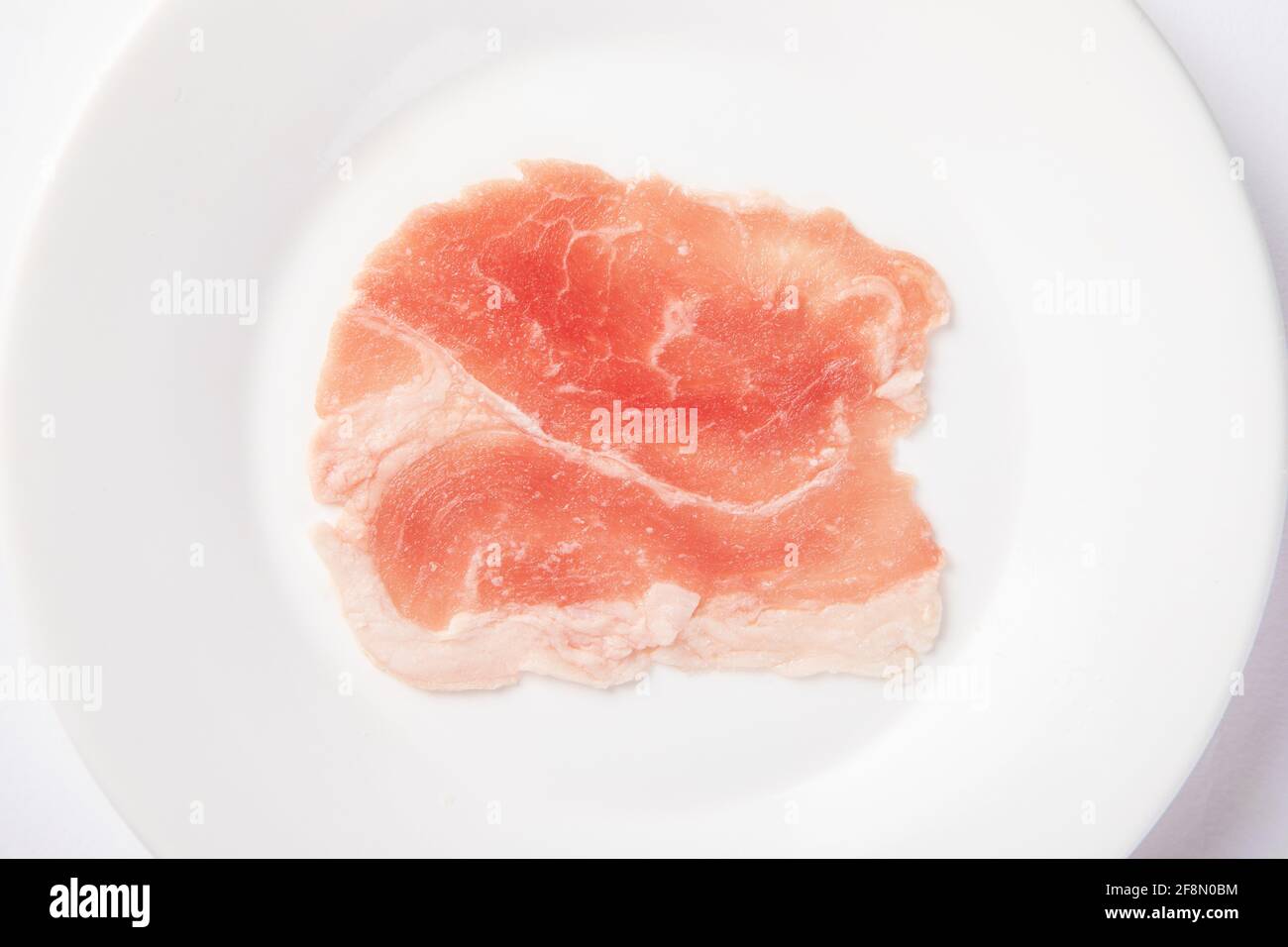 Top view of raw thin-sliced mutton on a white plate Stock Photo - Alamy