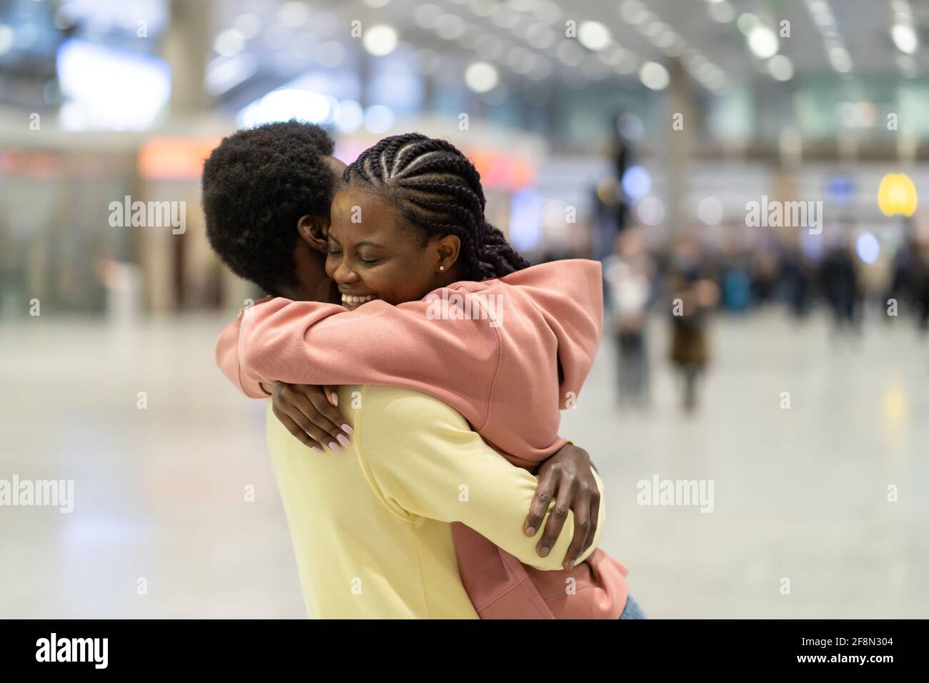 Family reunion in airport. Happy black male hugging excited woman after ...