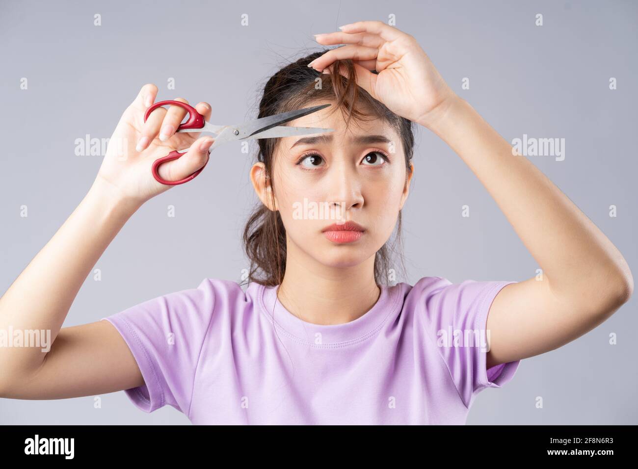 The young Asian girl was cutting her bangs with scissors Stock Photo ...