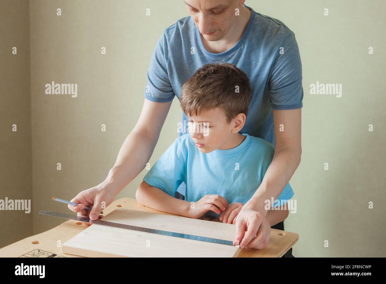 Cute little boy with pencil in hand making marks on wooden plank ...