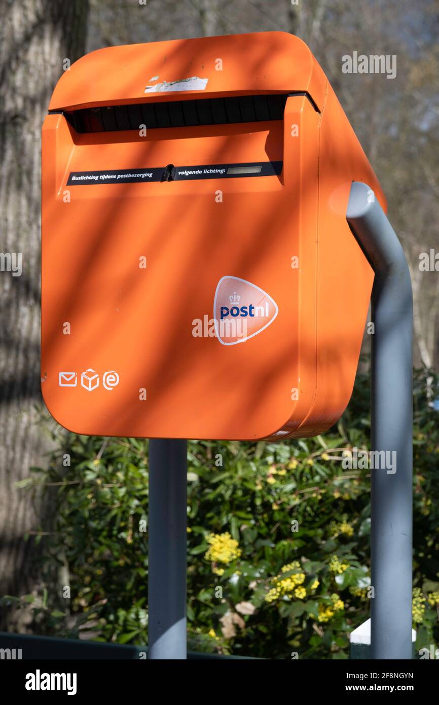 Typical Dutch orange letterbox with PostNL logo, which is outside in a ...