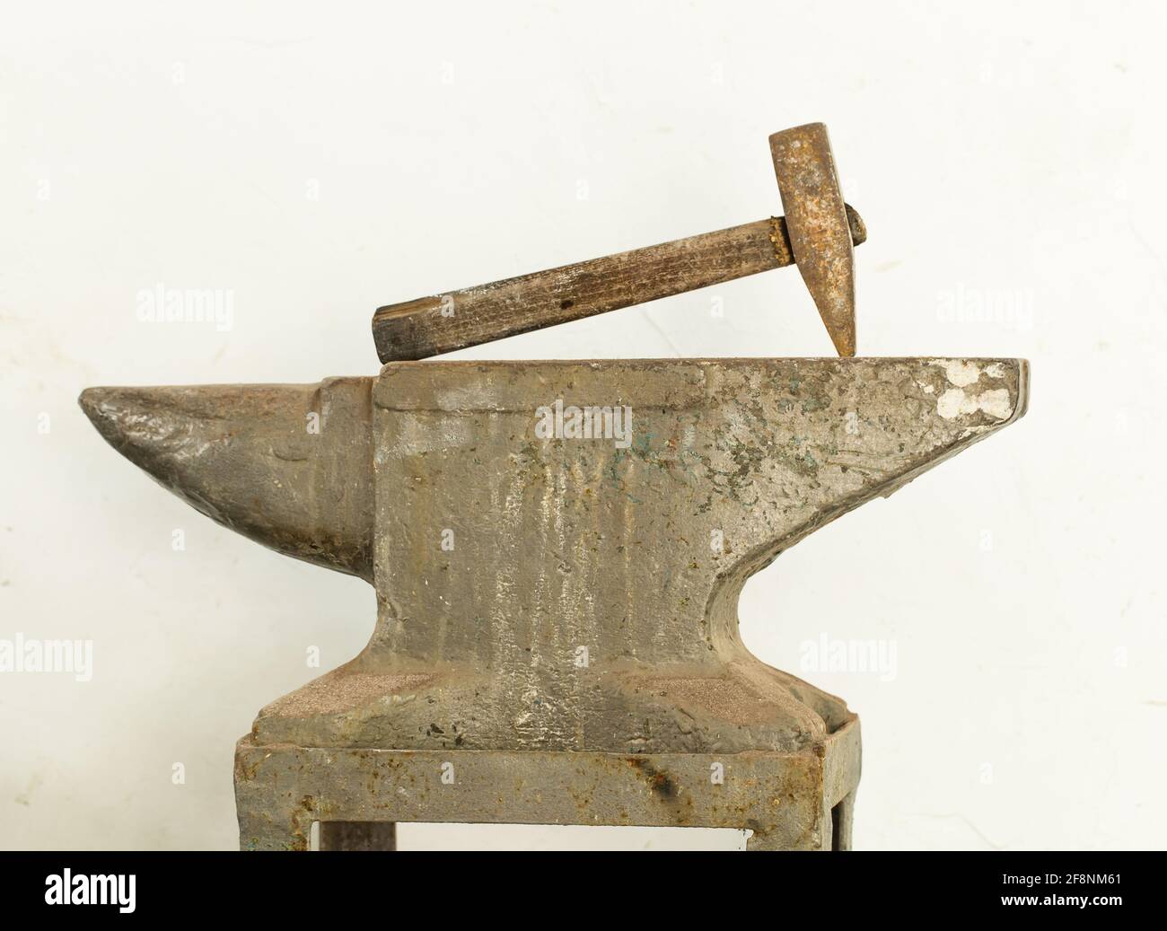 Old hammer and anvil tools against white clay wall as a background ...