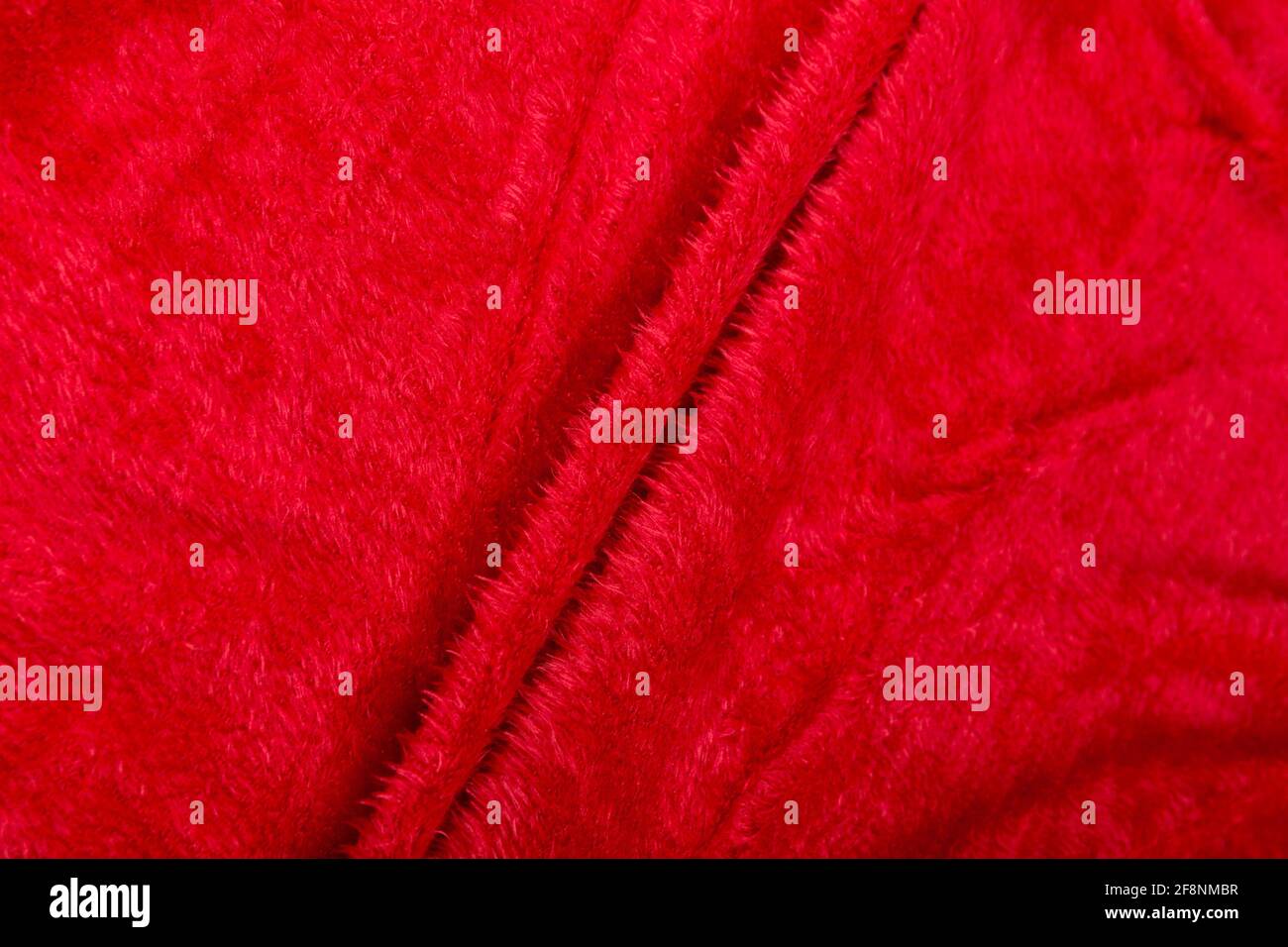Colored red textile satin fabric folded in folds and waves with ...