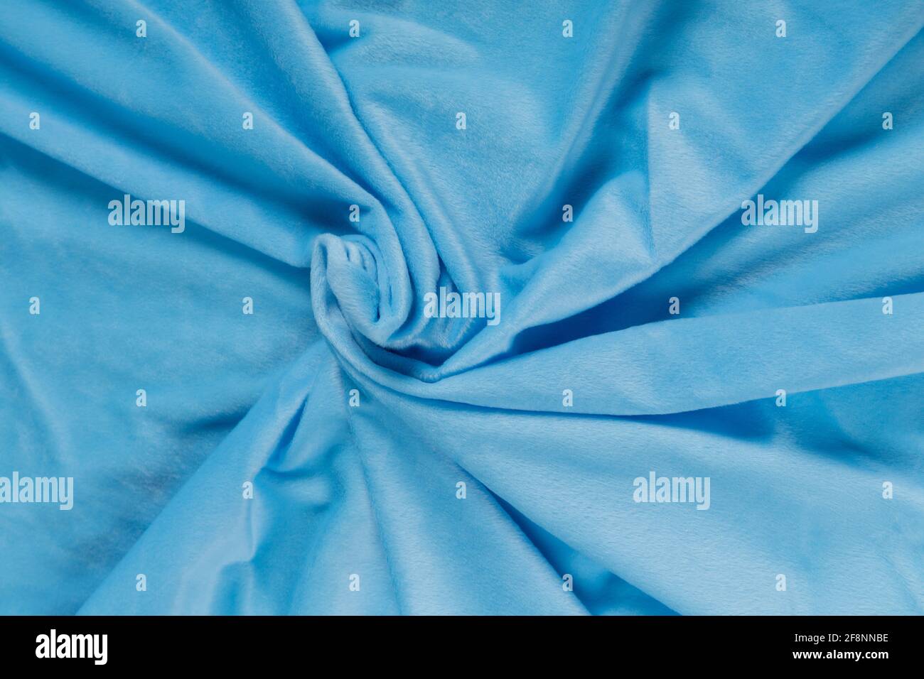 Colored blue textile satin fabric folded in folds and waves with ...