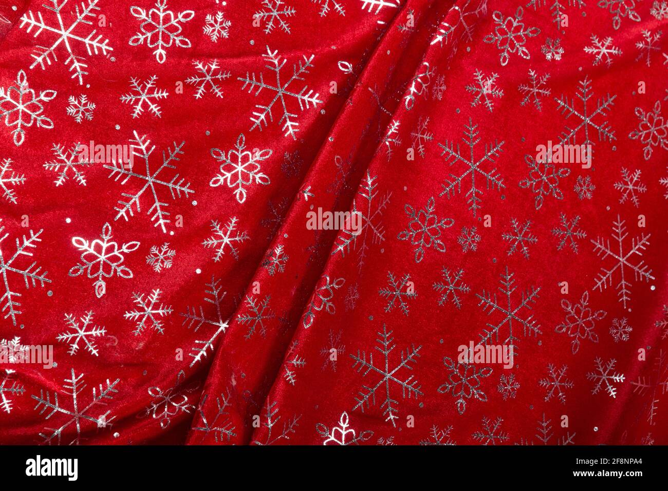 Colored red textile satin fabric folded in folds and waves with ...