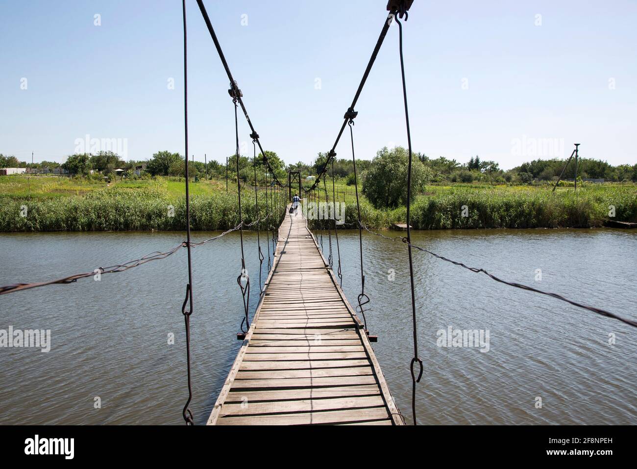 A man walks on a suspension bridge over the river Stock Photo - Alamy