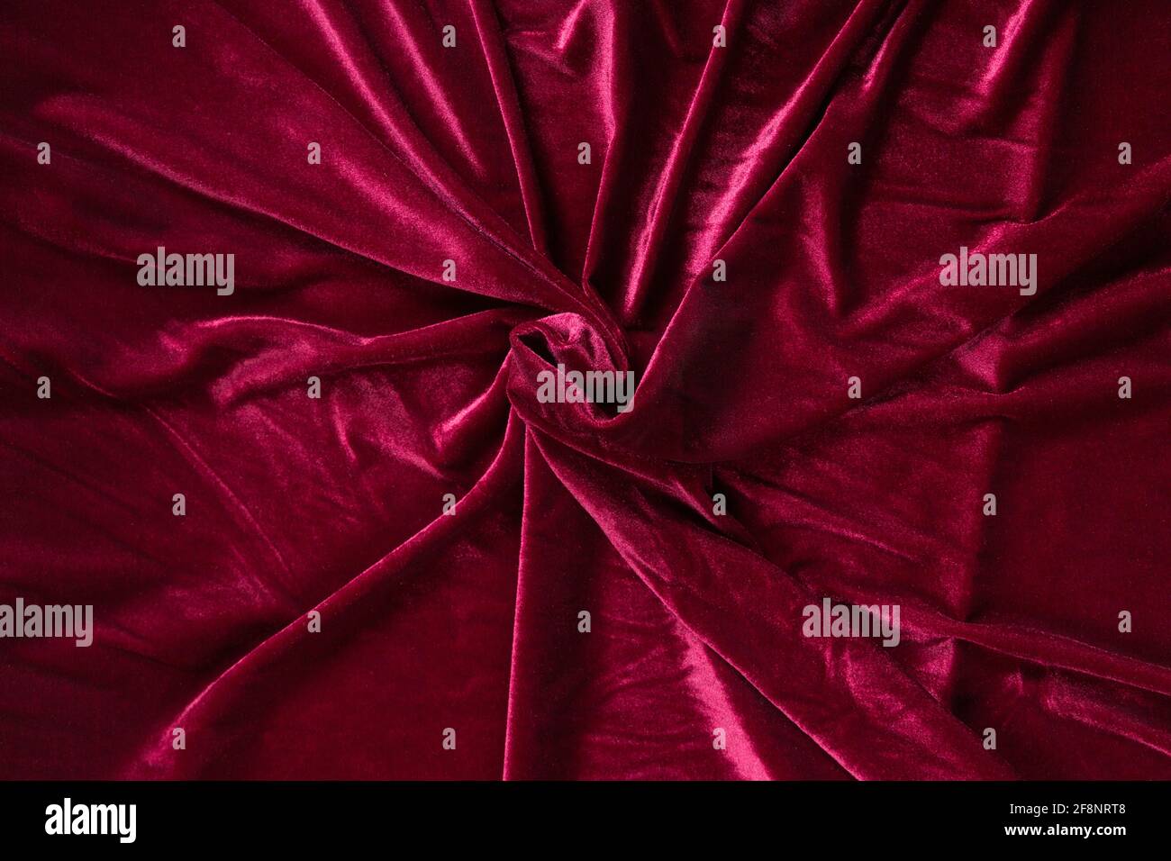 Colored red textile satin fabric folded in folds and waves with ...