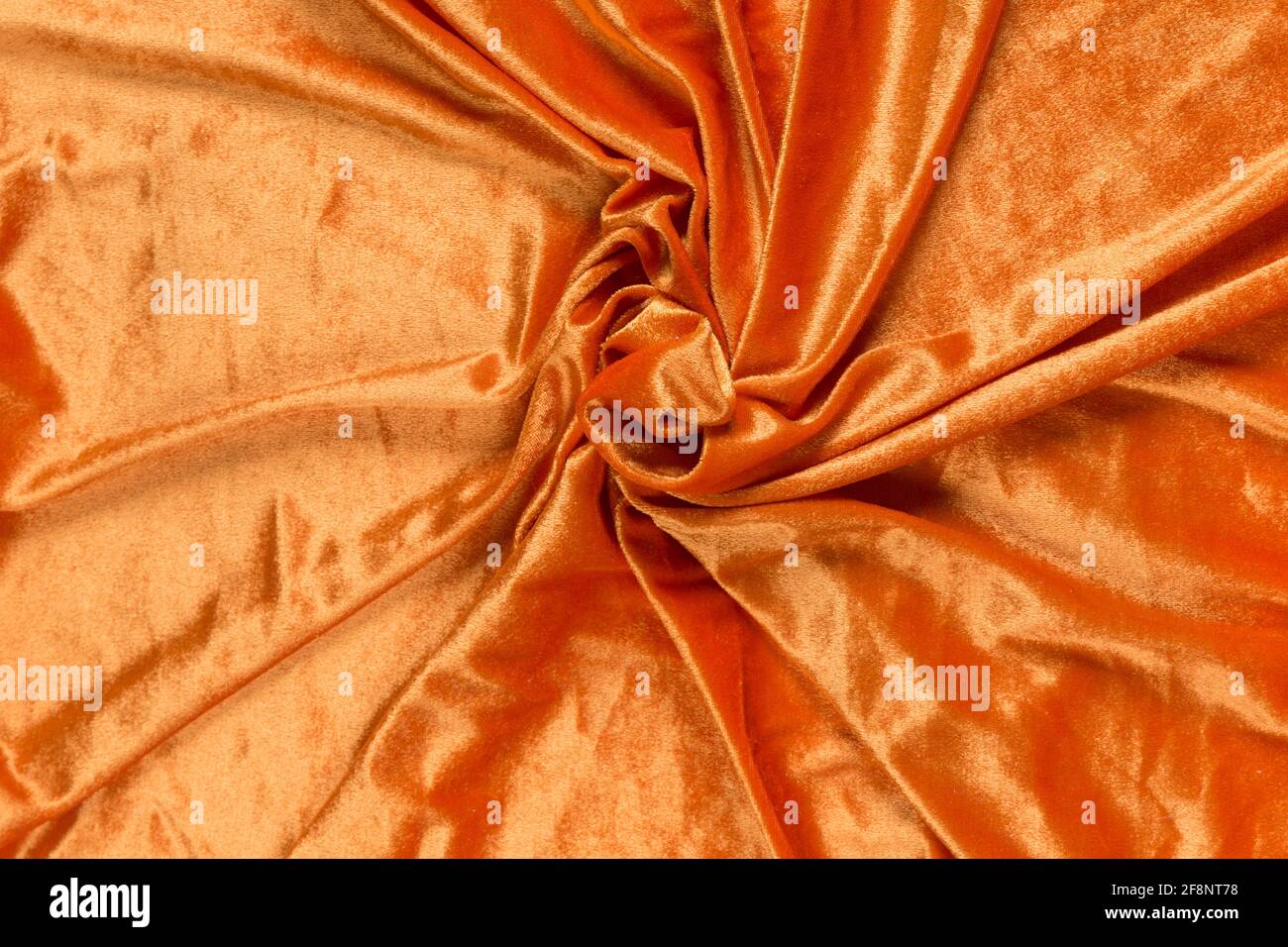 Colored orange textile satin fabric folded in folds and waves with ...