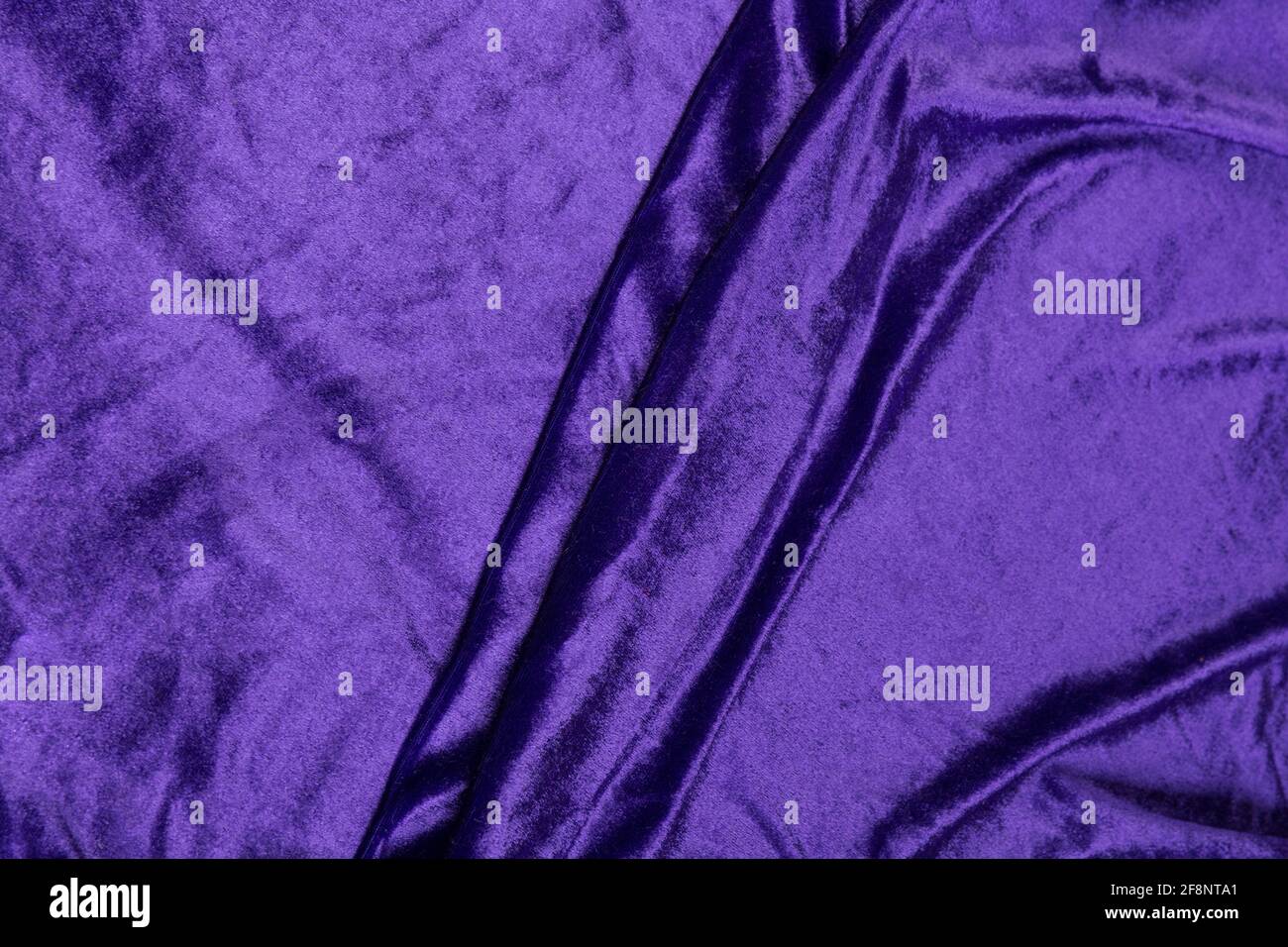 Colored violet textile satin fabric folded in folds and waves with ...