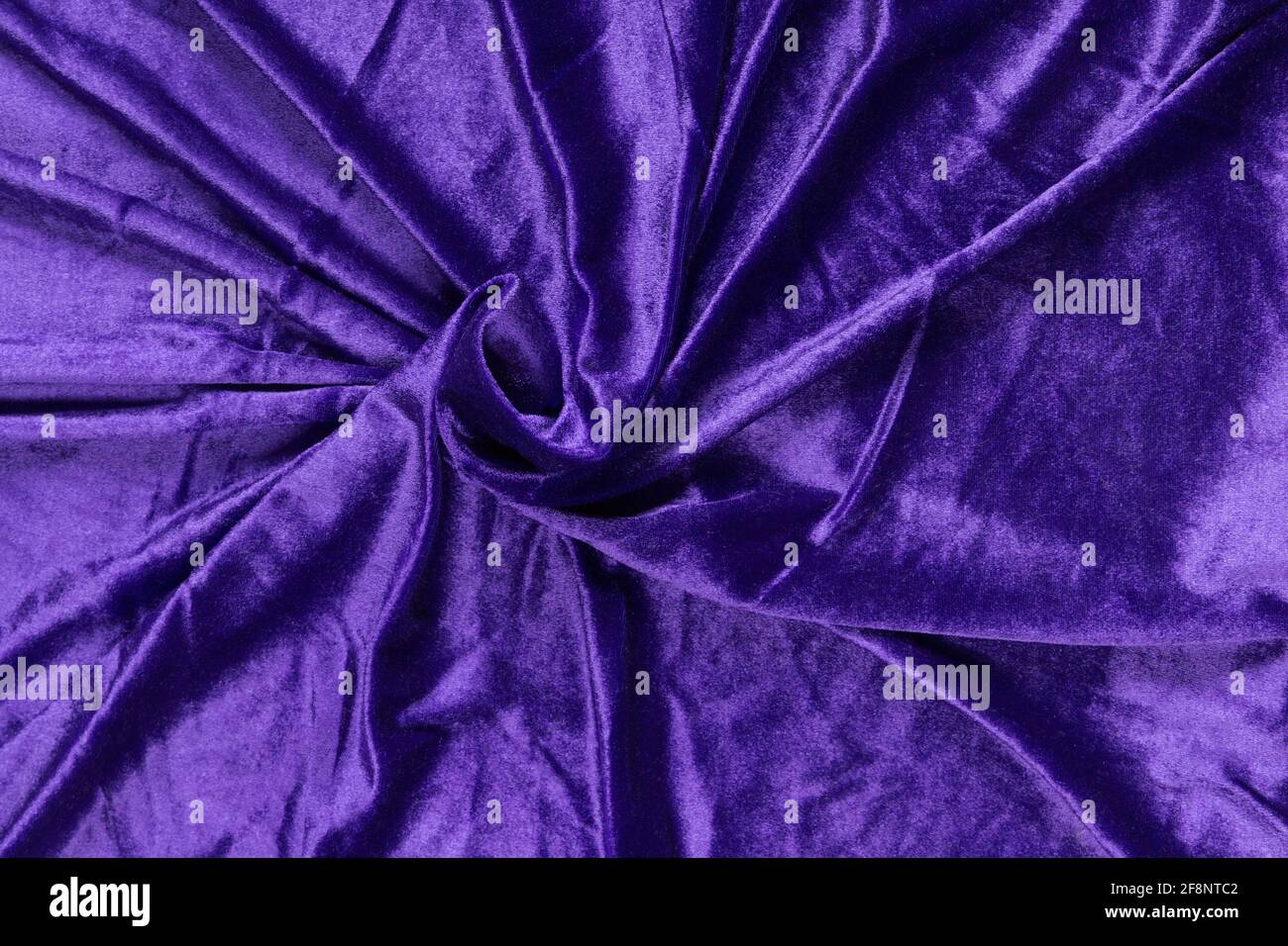 Colored violet textile satin fabric folded in folds and waves with ...