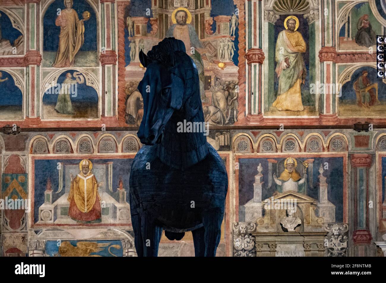 Sculpture of a black horse in the background of a fresco wall in ...