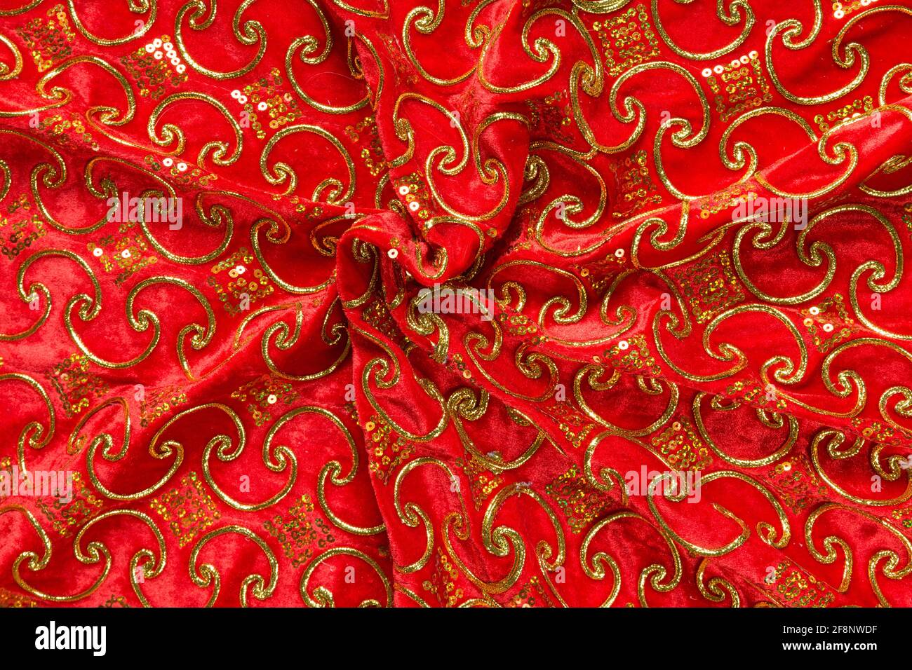 Colored red textile satin fabric folded in folds and waves with ...