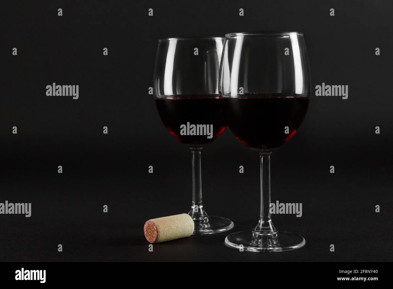 Two glass glasses of red wine on a black homogeneous background in the ...