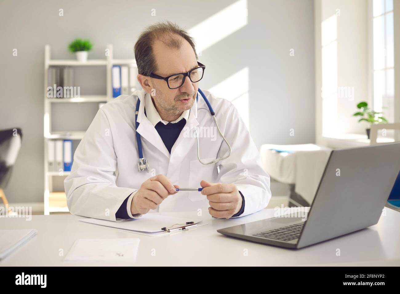 Doctor having online video call remote consultation on laptop at clinic ...