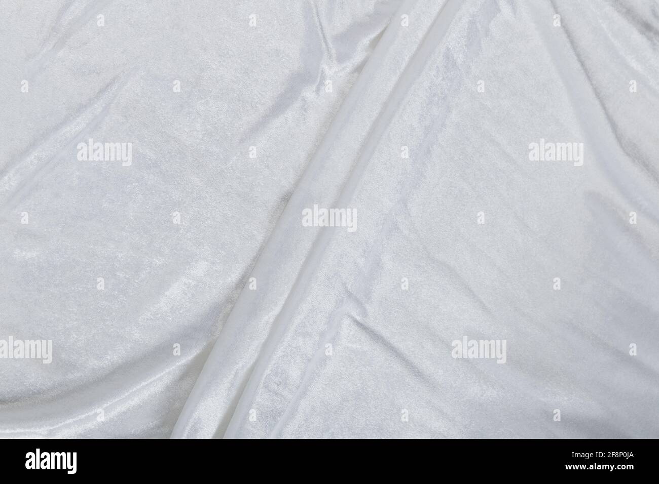 Colored white textile satin fabric folded in folds and waves with ...