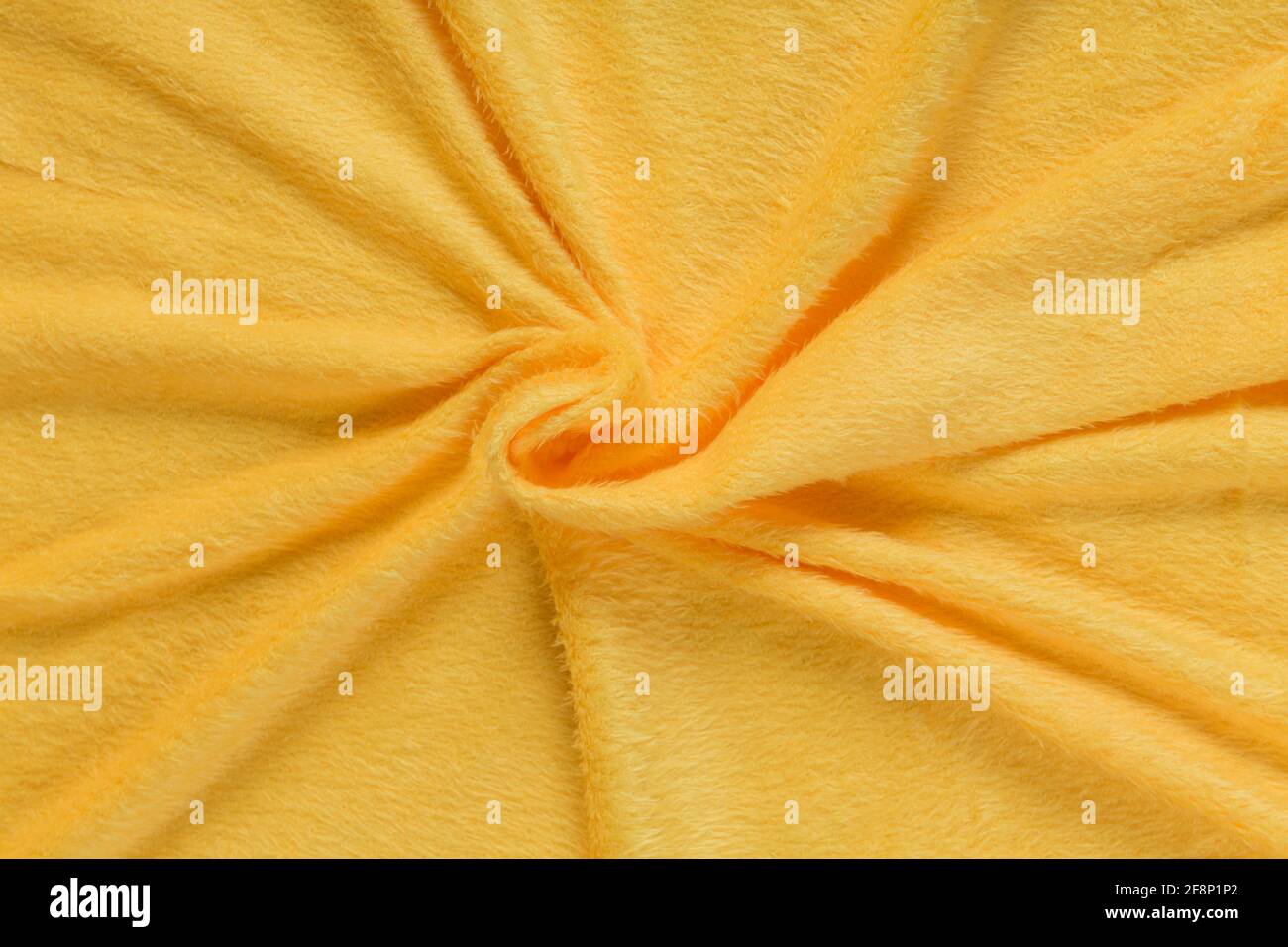Colored yellow textile satin fabric folded in folds and waves with ...