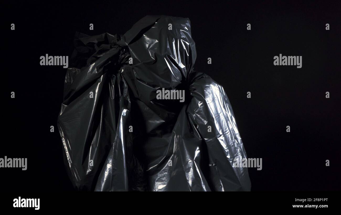 Human in black garbage bag on black Stock Photo - Alamy