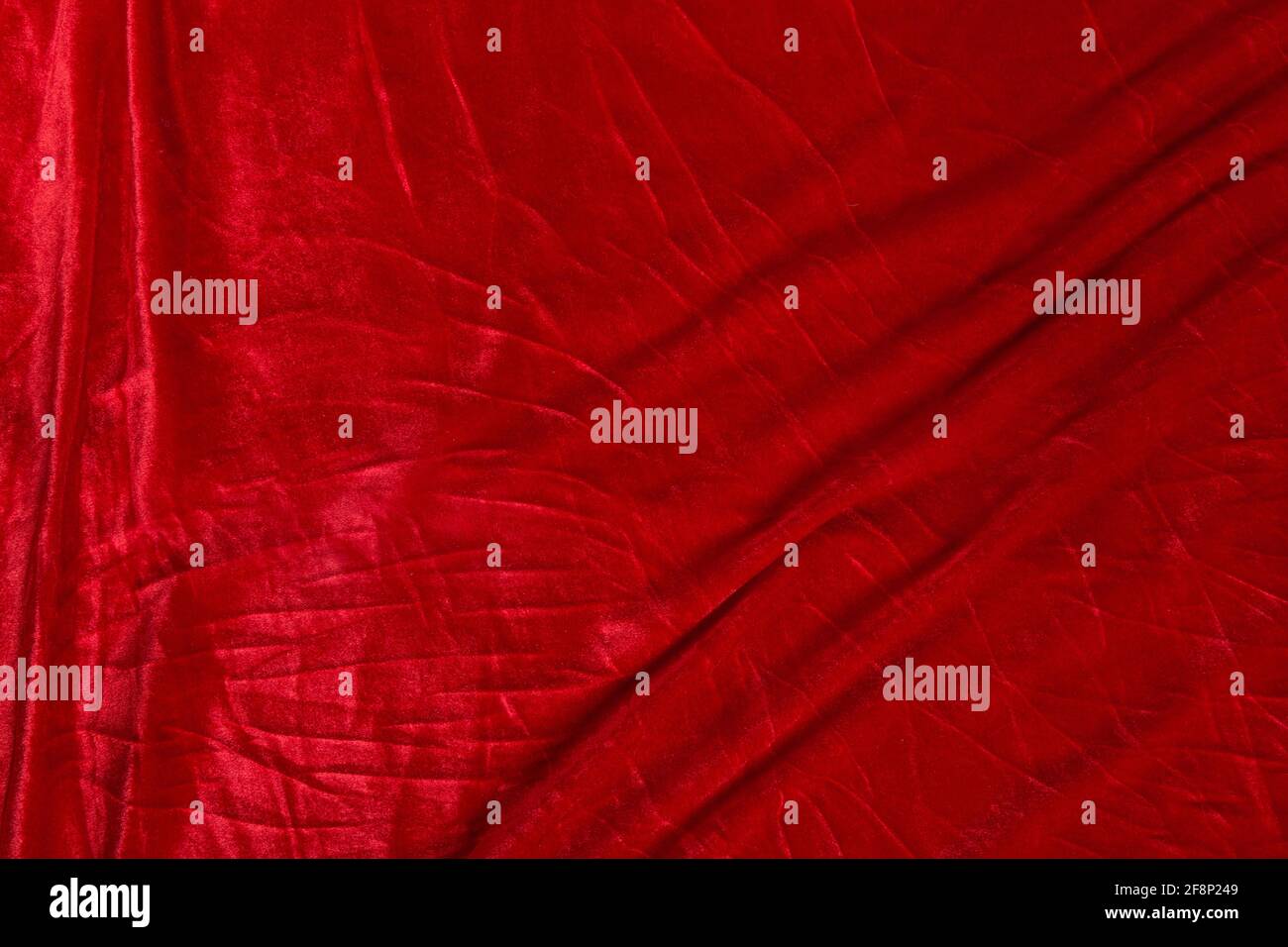 Colored red textile satin fabric folded in folds and waves with ...