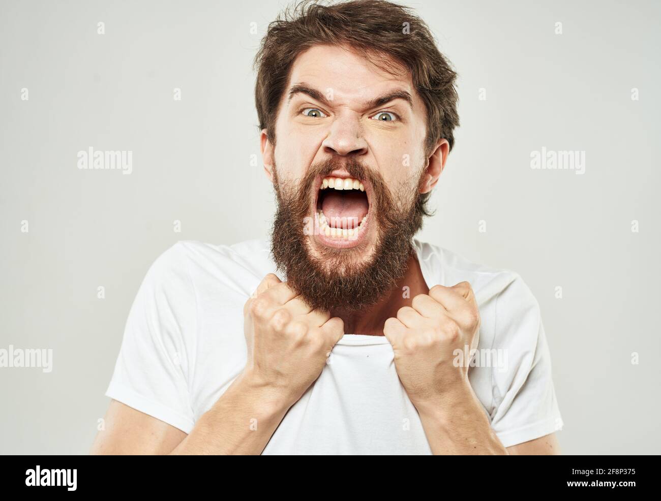 Aggressive man in a white T-shirt irritability emotions light ...