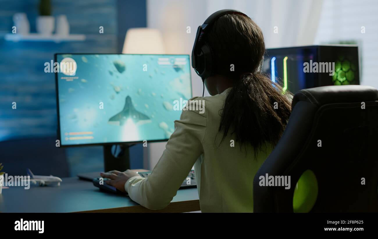 Competitive african gamer sitting on gaming chair, using headphone ...