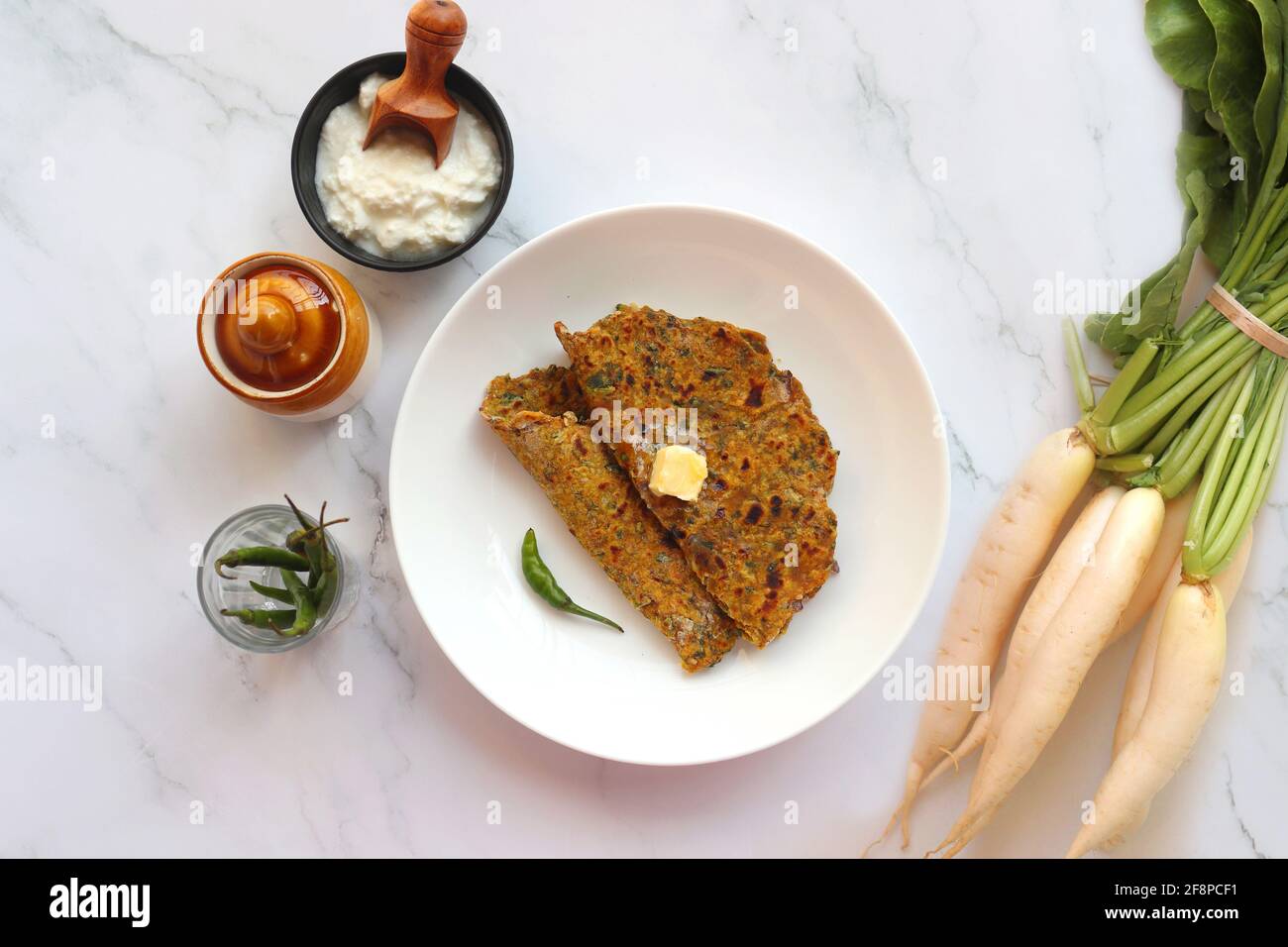 Radish Or Mooli Masala Paratha Served On A White Plate With Butter Cubes Served With Curd