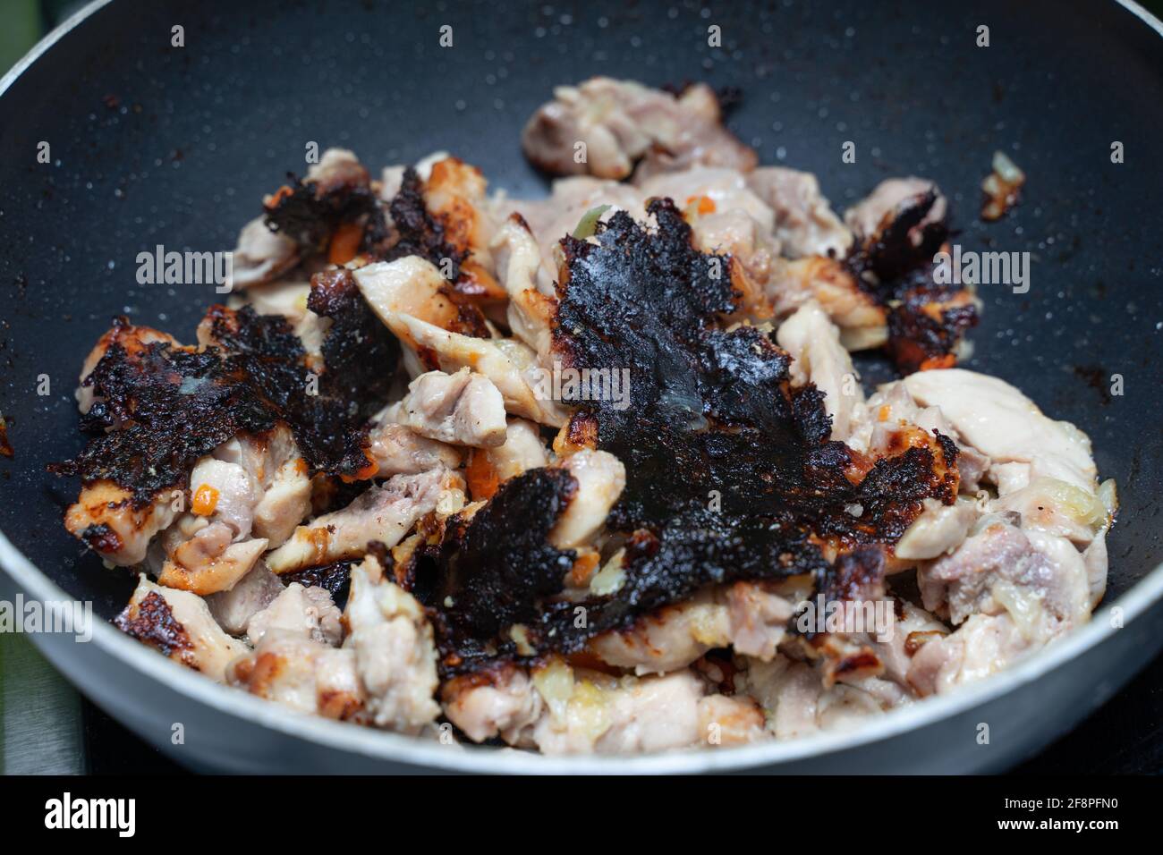 burnt pieces of chicken in a pan. spoiled food Stock Photo - Alamy